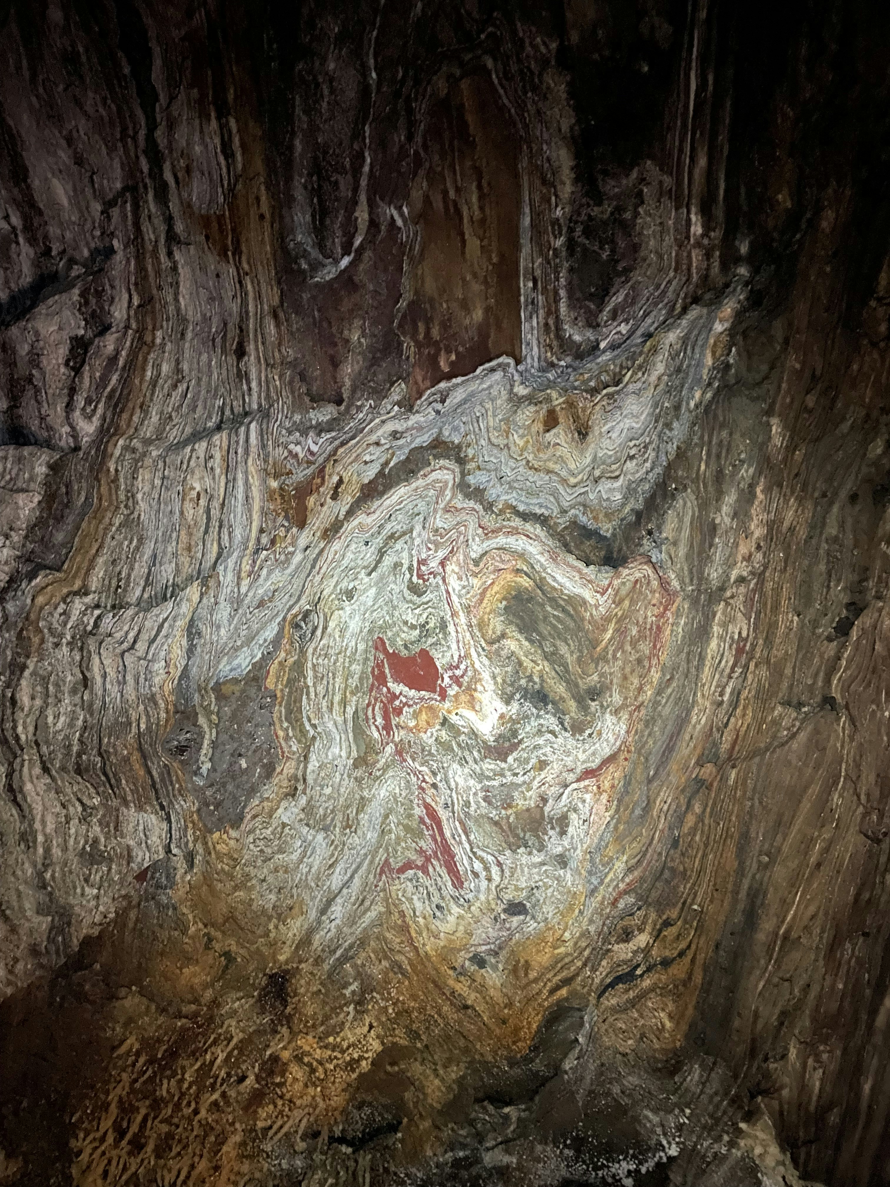 Intricate patterns of layered rock formations showcasing rich hues of red, gray, and cream. The natural textures reveal the geological history of the earth.