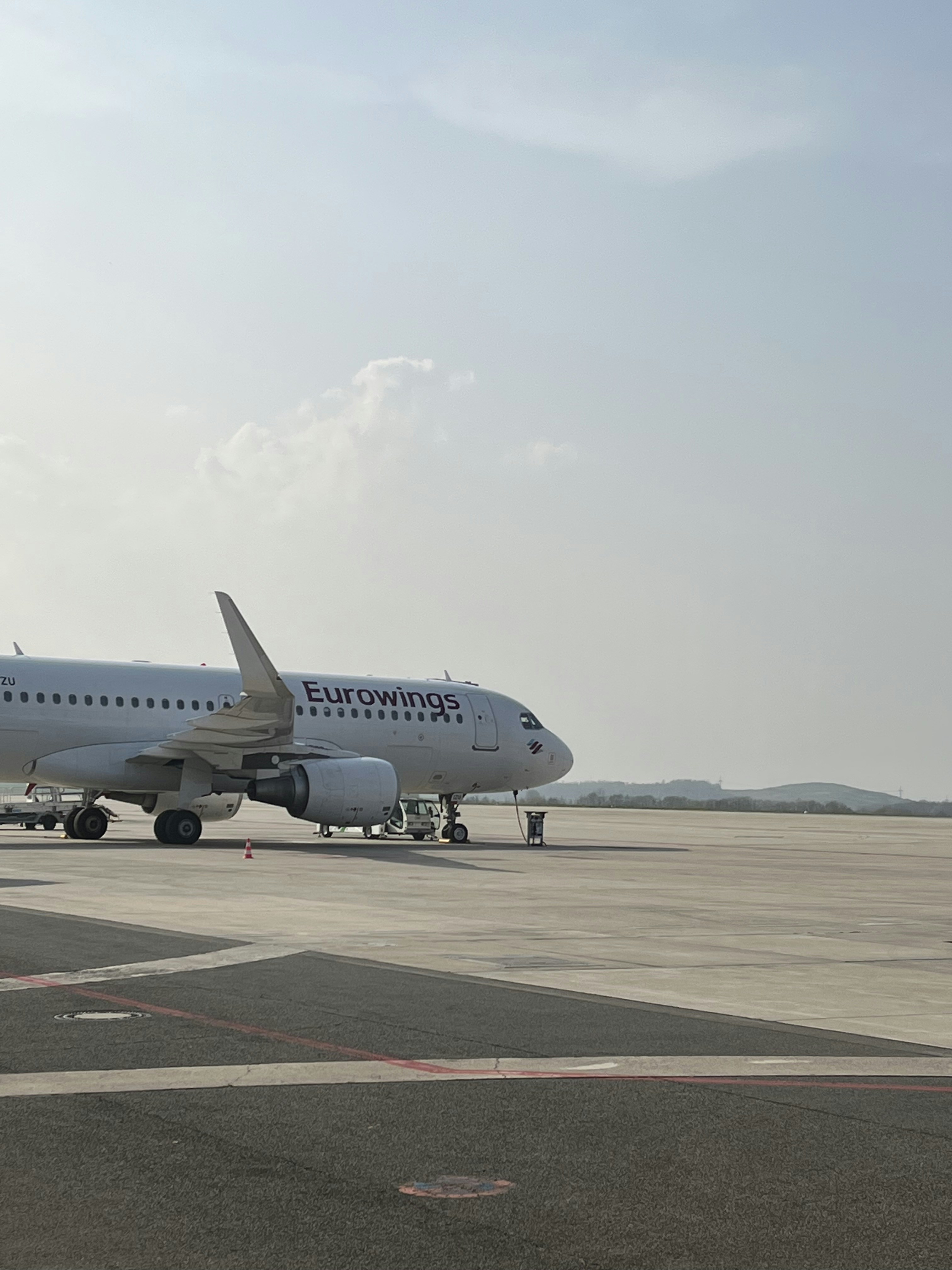 Airplane parked on a sunny airport runway with clear skies overhead.