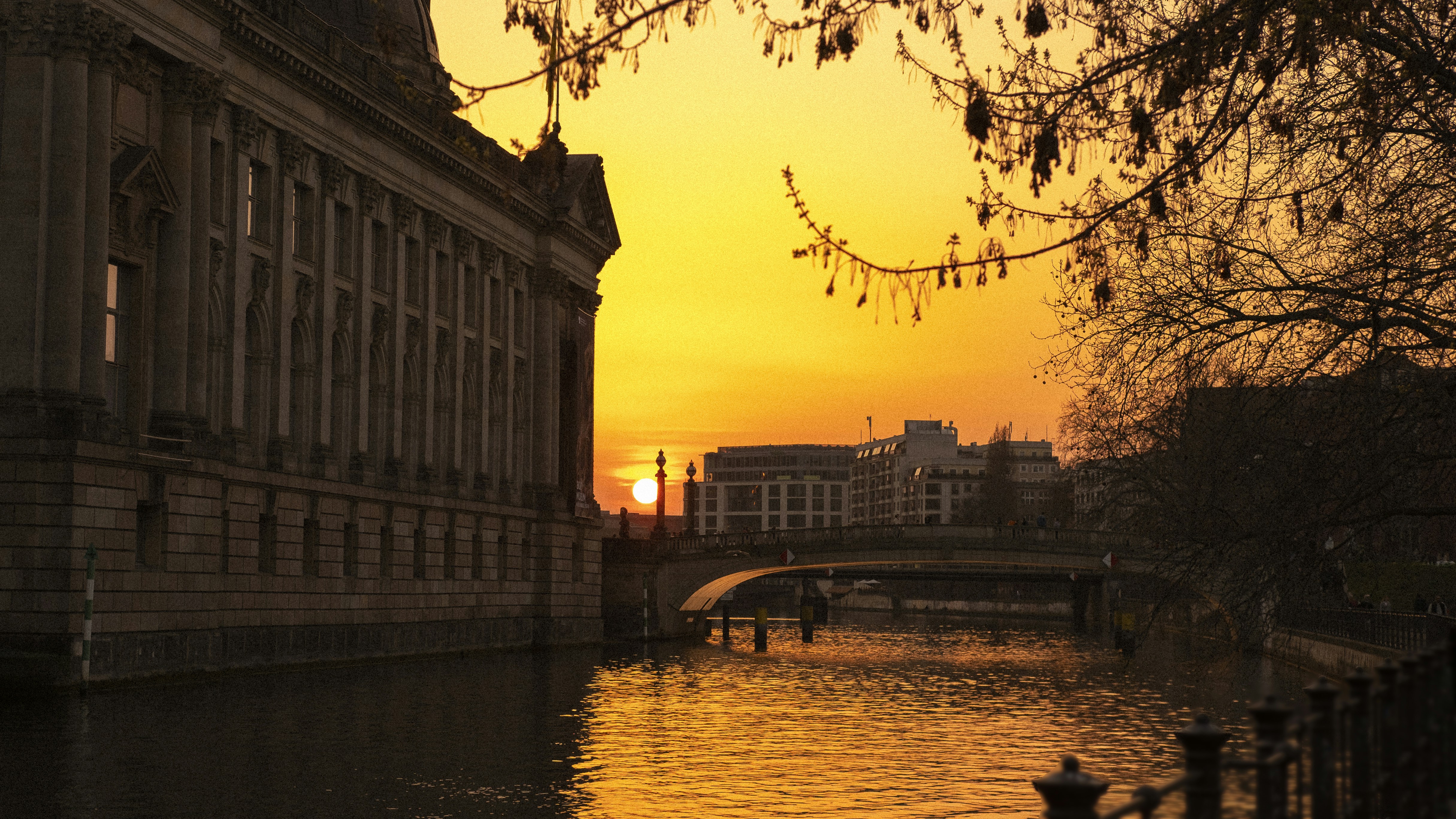 The sun is setting over a river in a city photo – Free Building Image ...