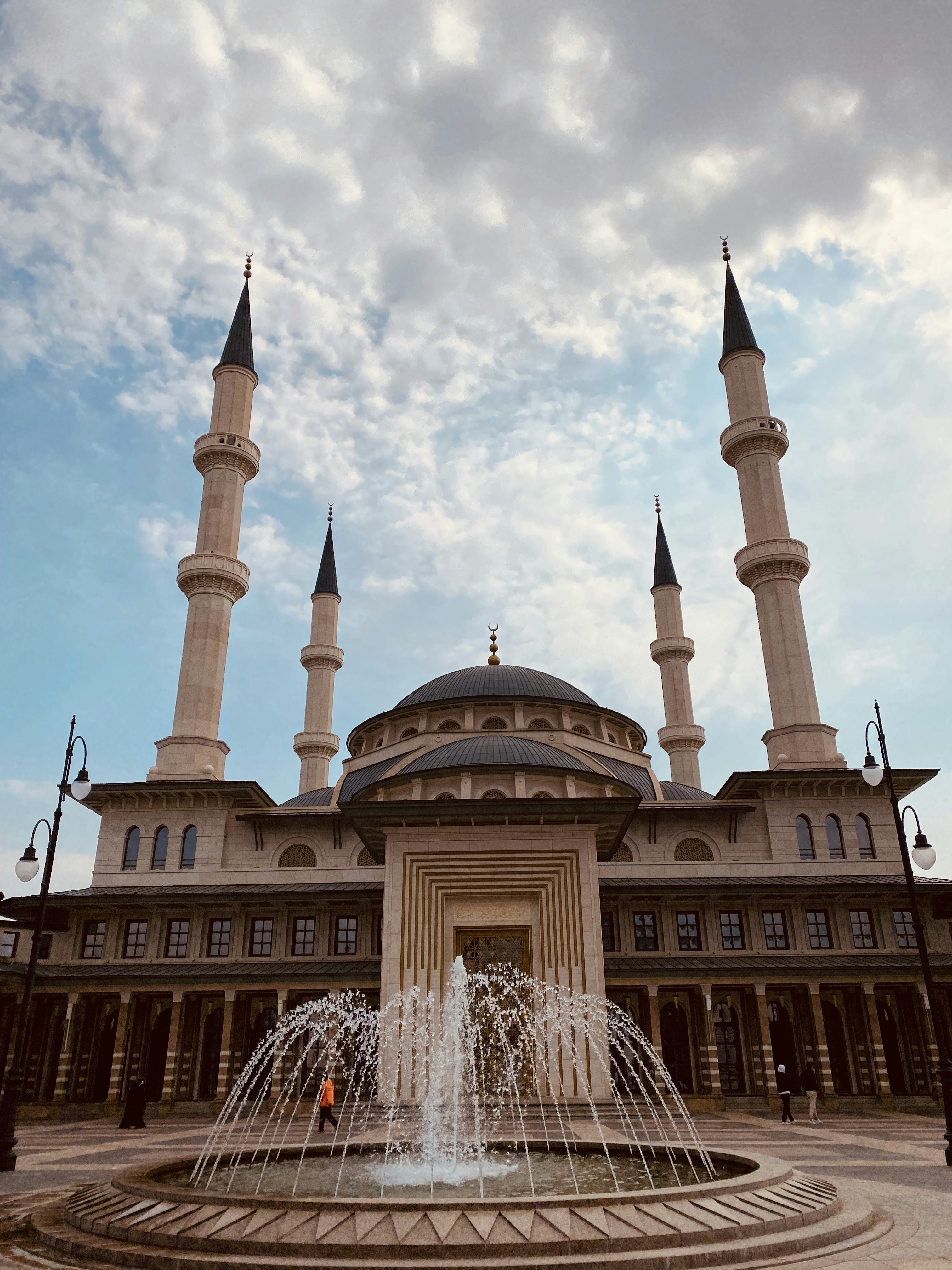 Grand mosque with towering minarets and a central dome, framed by a decorative fountain in the foreground. A blend of architectural elegance and serene ambiance.