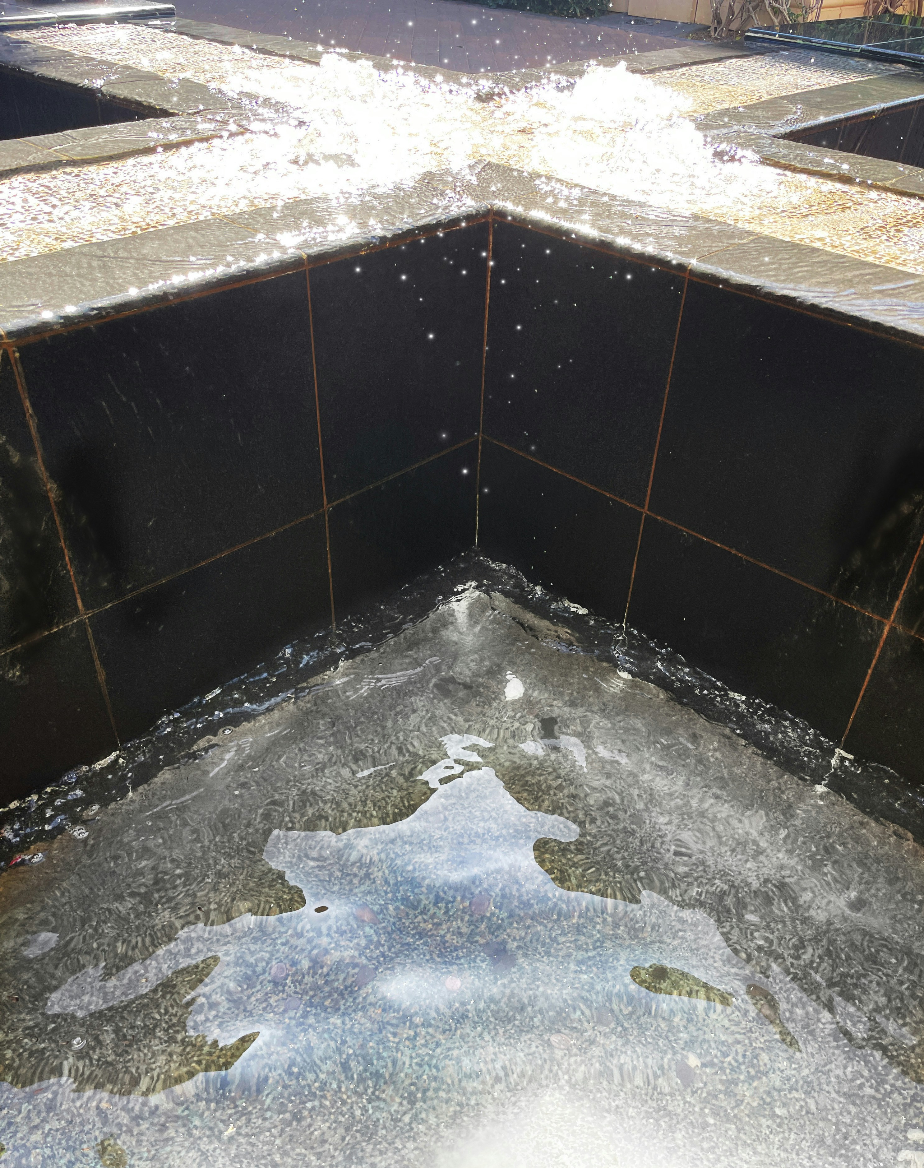 Ice on Edge: The Quiet Corner of a Dark-Tiled Fountain