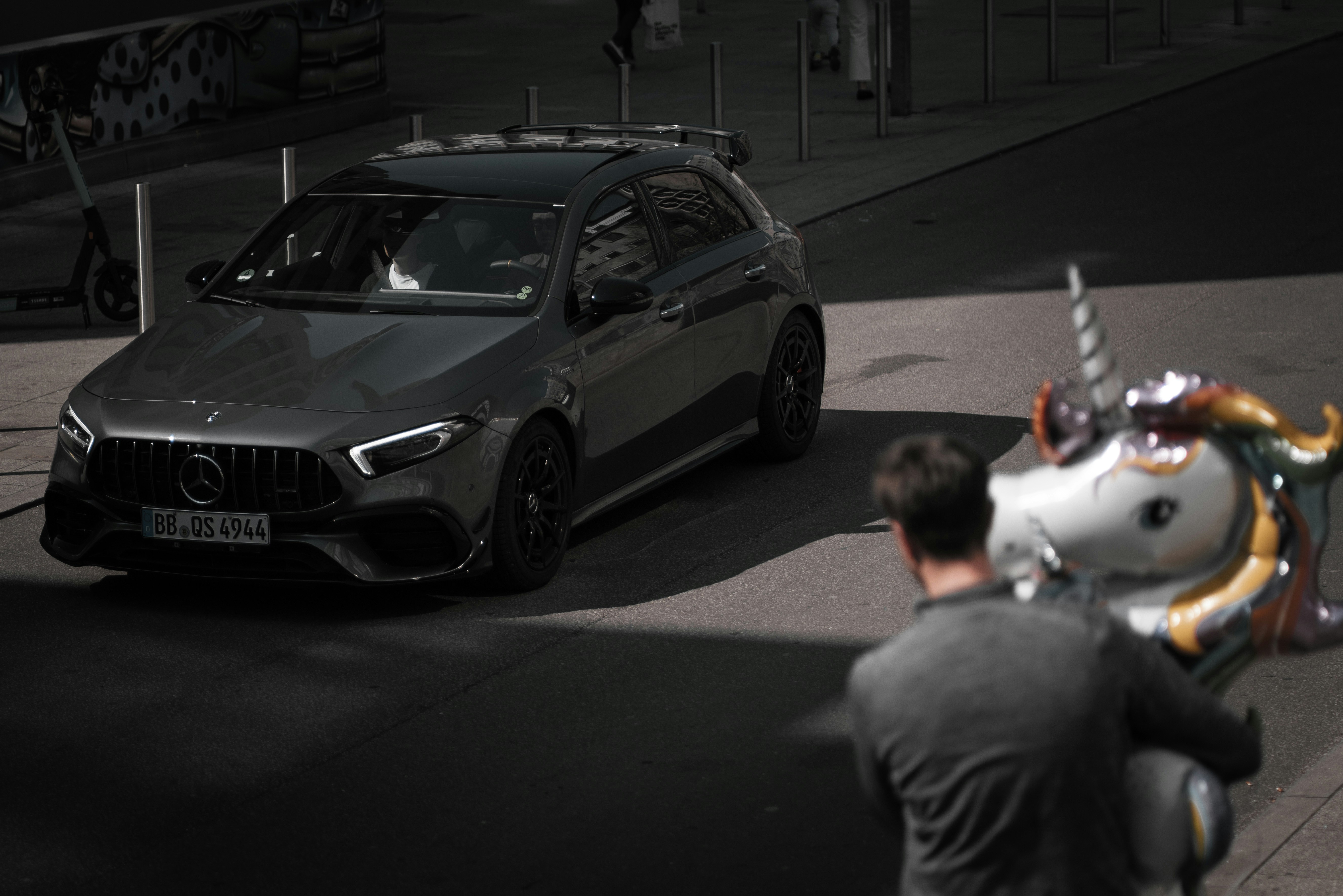 a man taking a picture of a car with a unicorn balloon attached to itMarcel Strauß