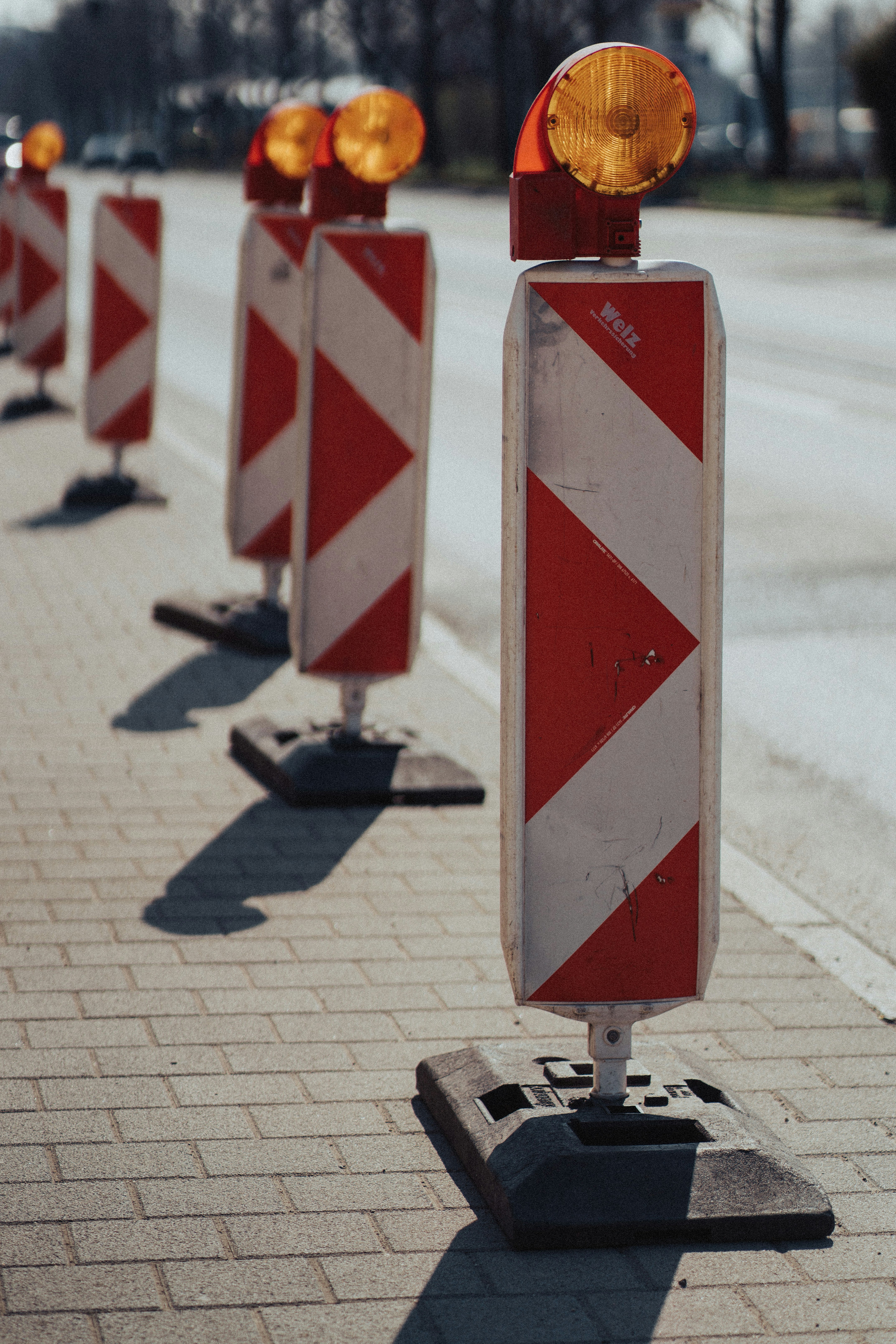 A row of red and white traffic signs sitting on the side of a road ...
