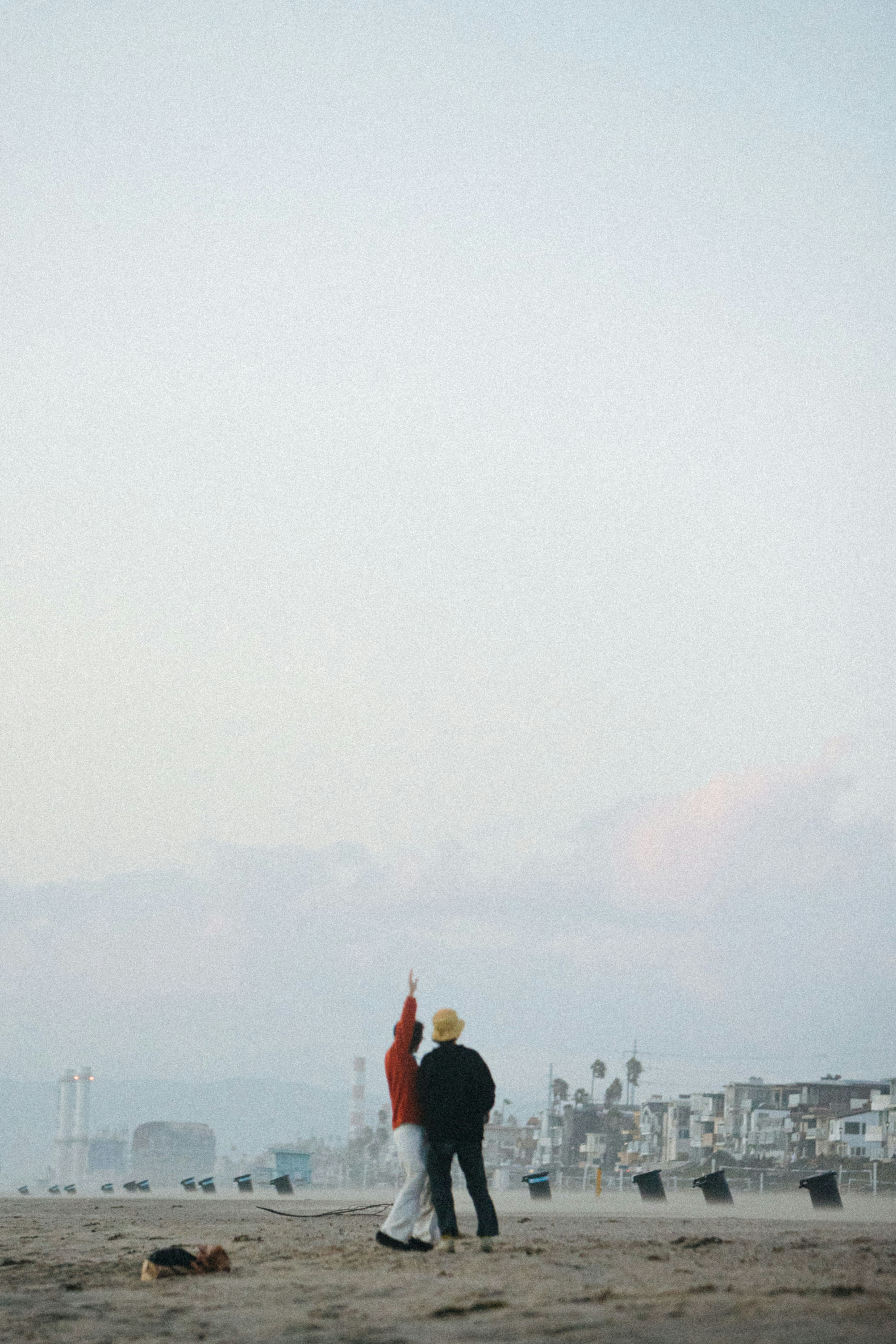 Coastal Silhouette: A Couple Embraces the Moment as a Dog Rests at the Shore