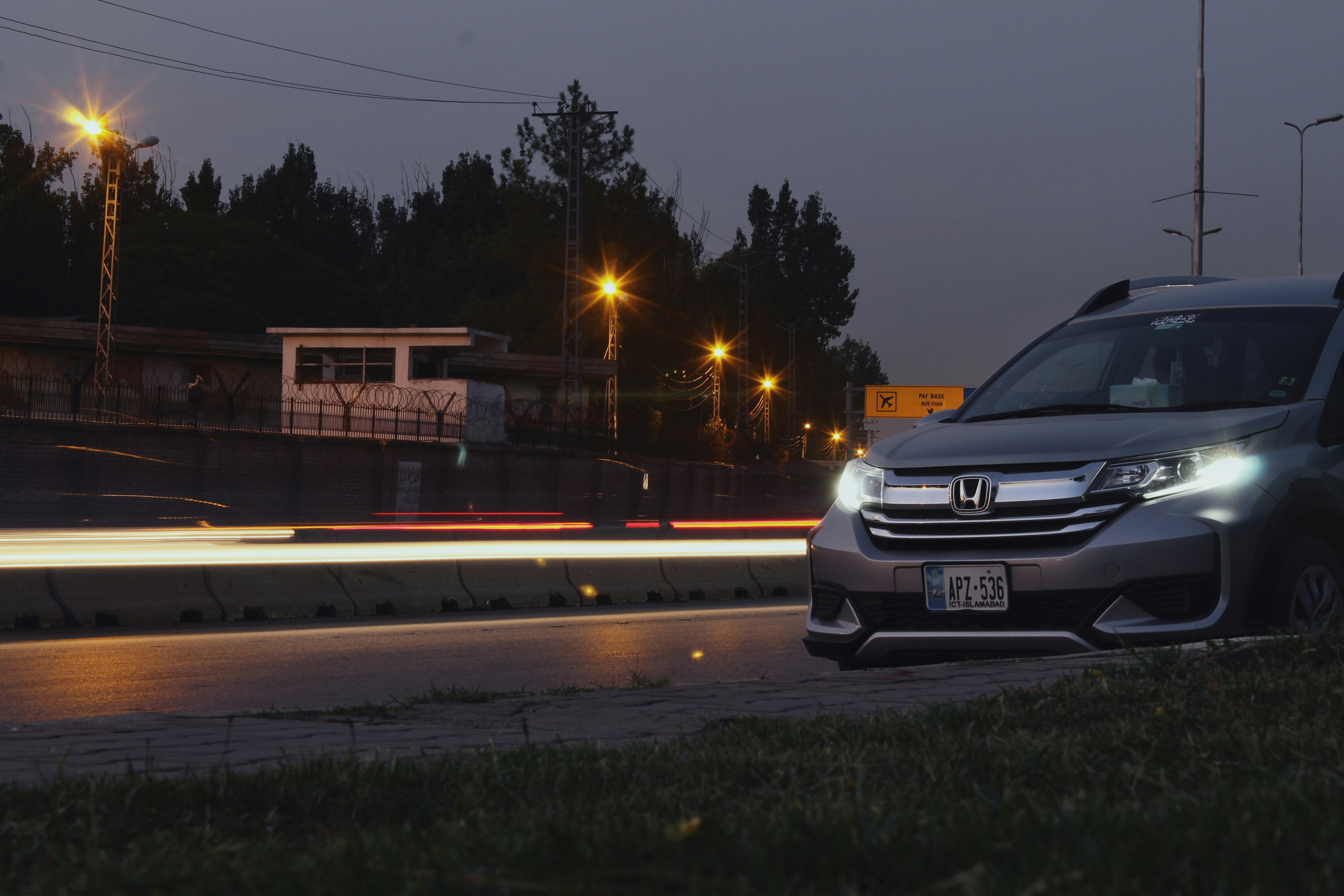 Midnight Honda: A Quiet Foreground Car Against a Corridor of Light Trails