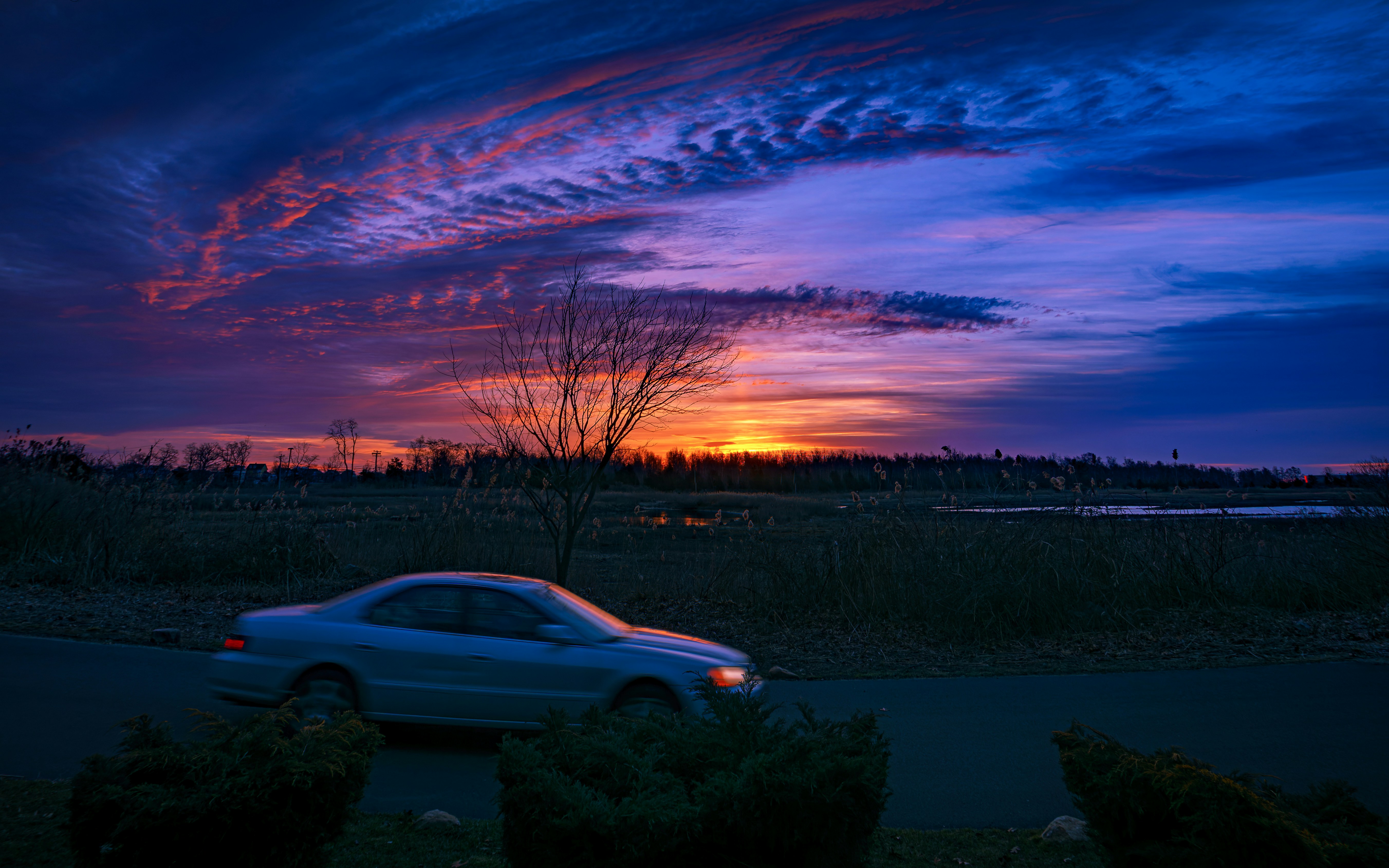 a car parked on the side of a road at sunset