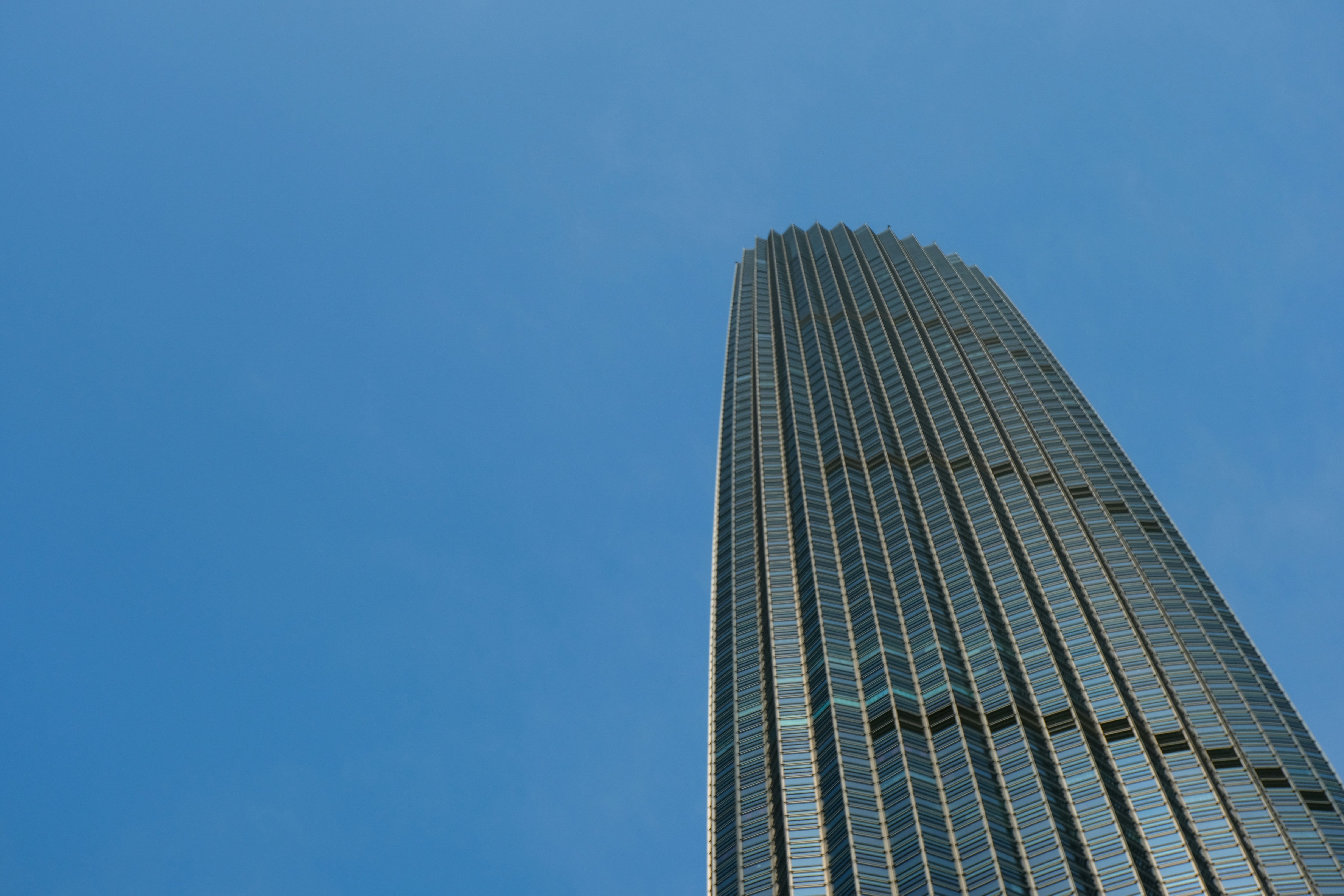 A very tall building towering over a blue sky photo – Free Grey Image ...