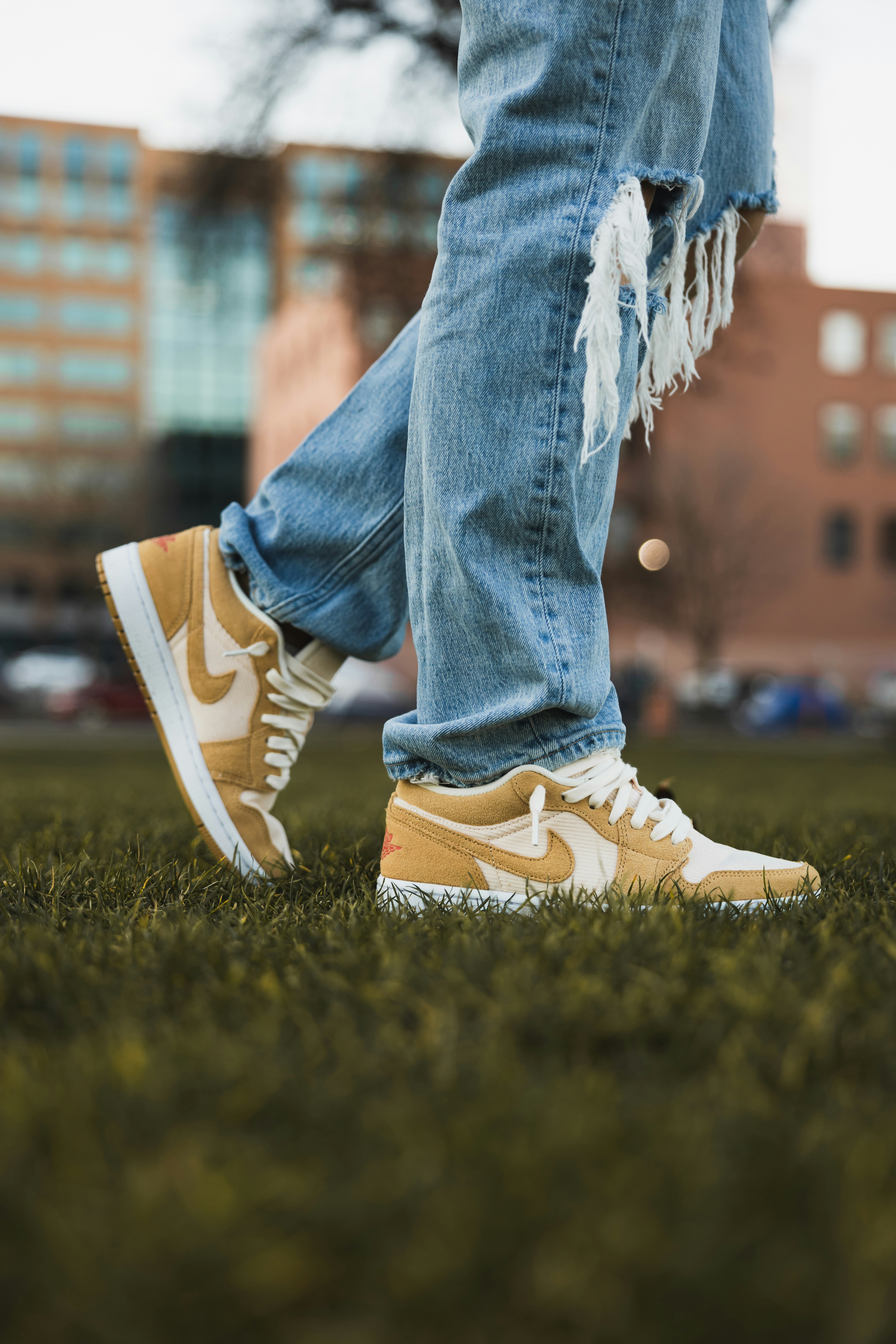 Midstep on the Campus Lawn: Tan Sneakers and Frayed Denim