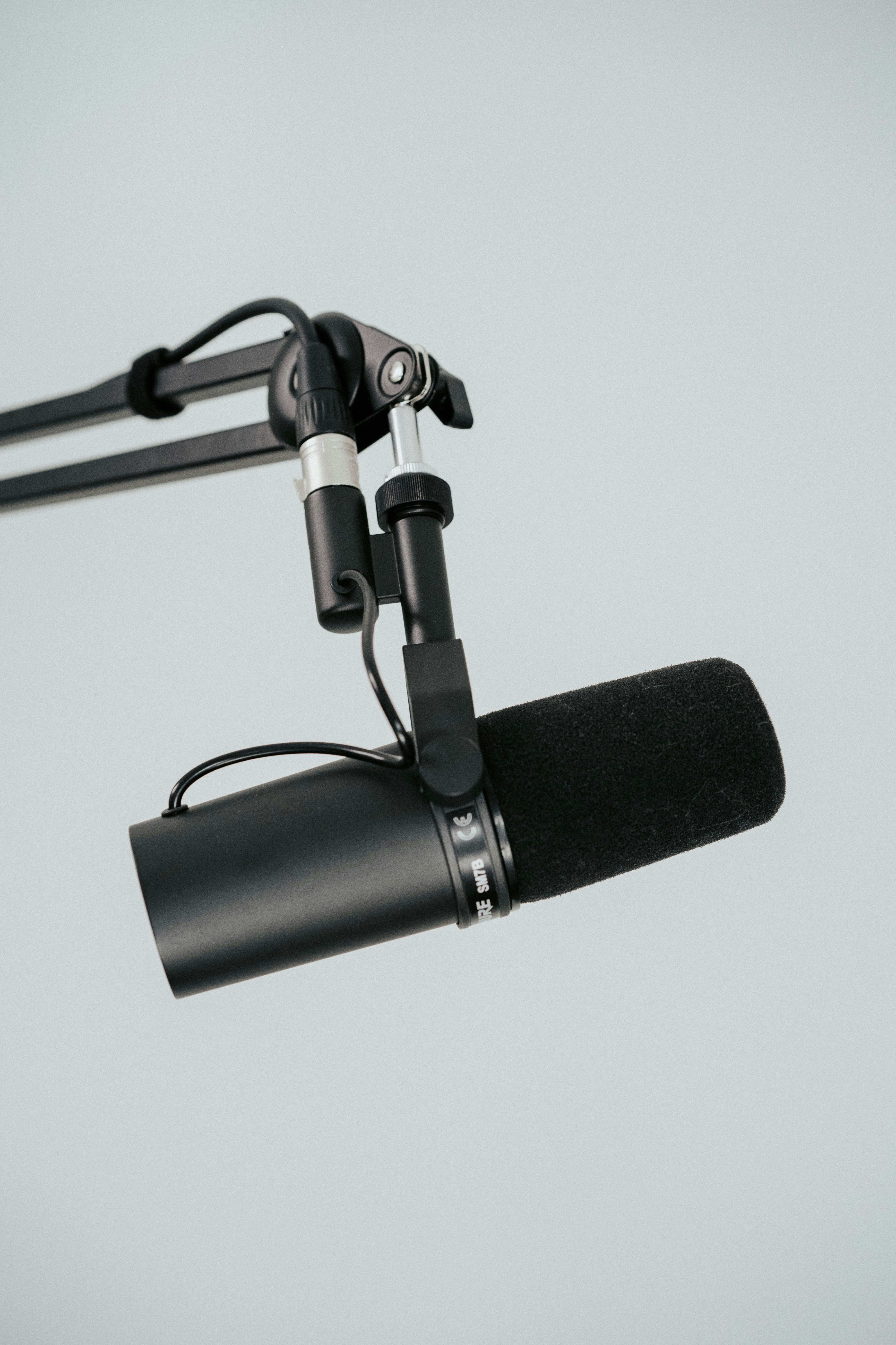 Professional microphone mounted on an adjustable arm against a soft gray backdrop.