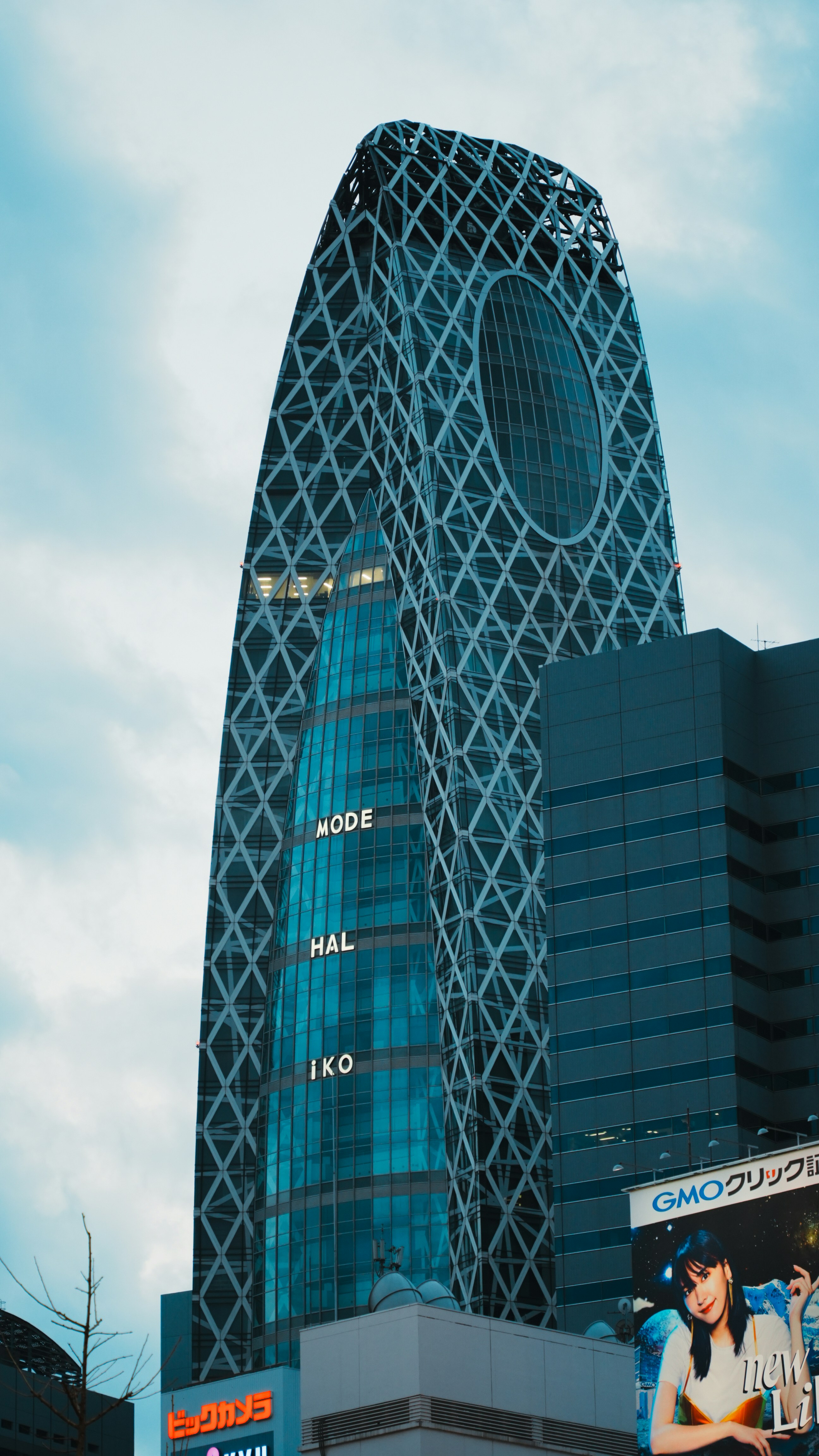 A striking modern skyscraper featuring a unique lattice design, showcasing a blend of glass and steel against a cloudy sky.