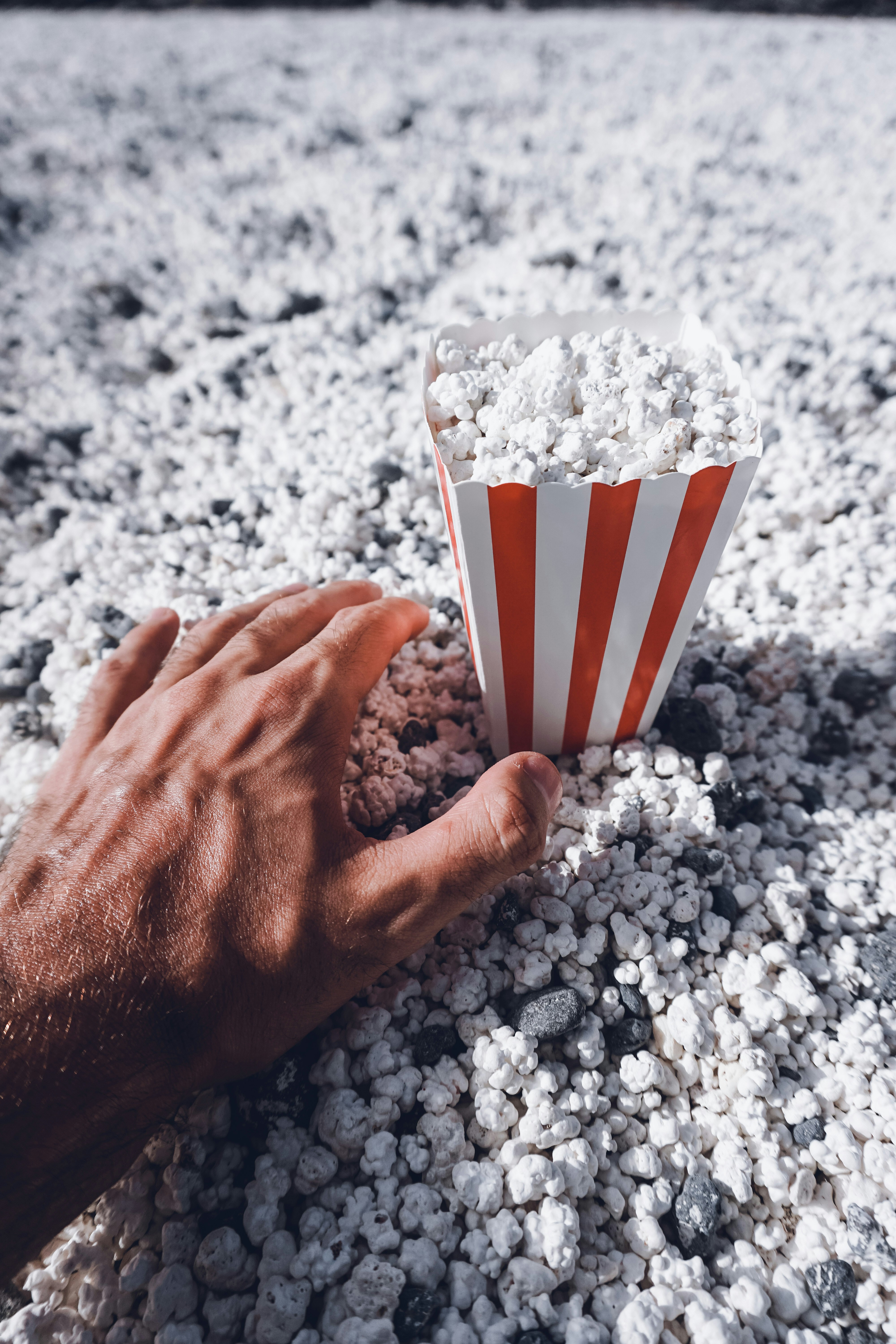 Crystalline Sea and an Orange-Striped Popcorn Cup: A Hand Reaches for a Quiet Snack