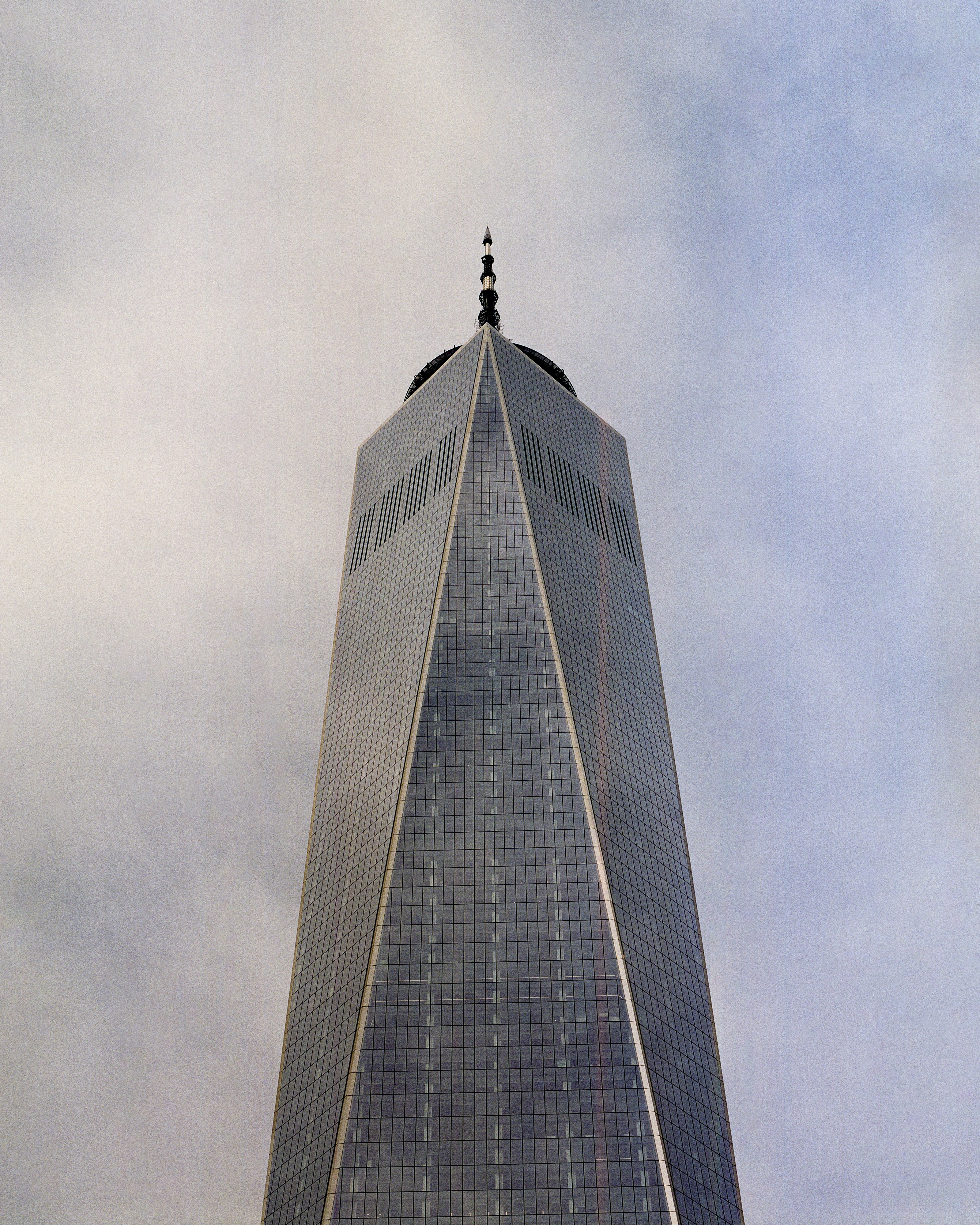 The One World Trade Center rises majestically against a soft, cloudy backdrop, symbolizing strength and renewal.