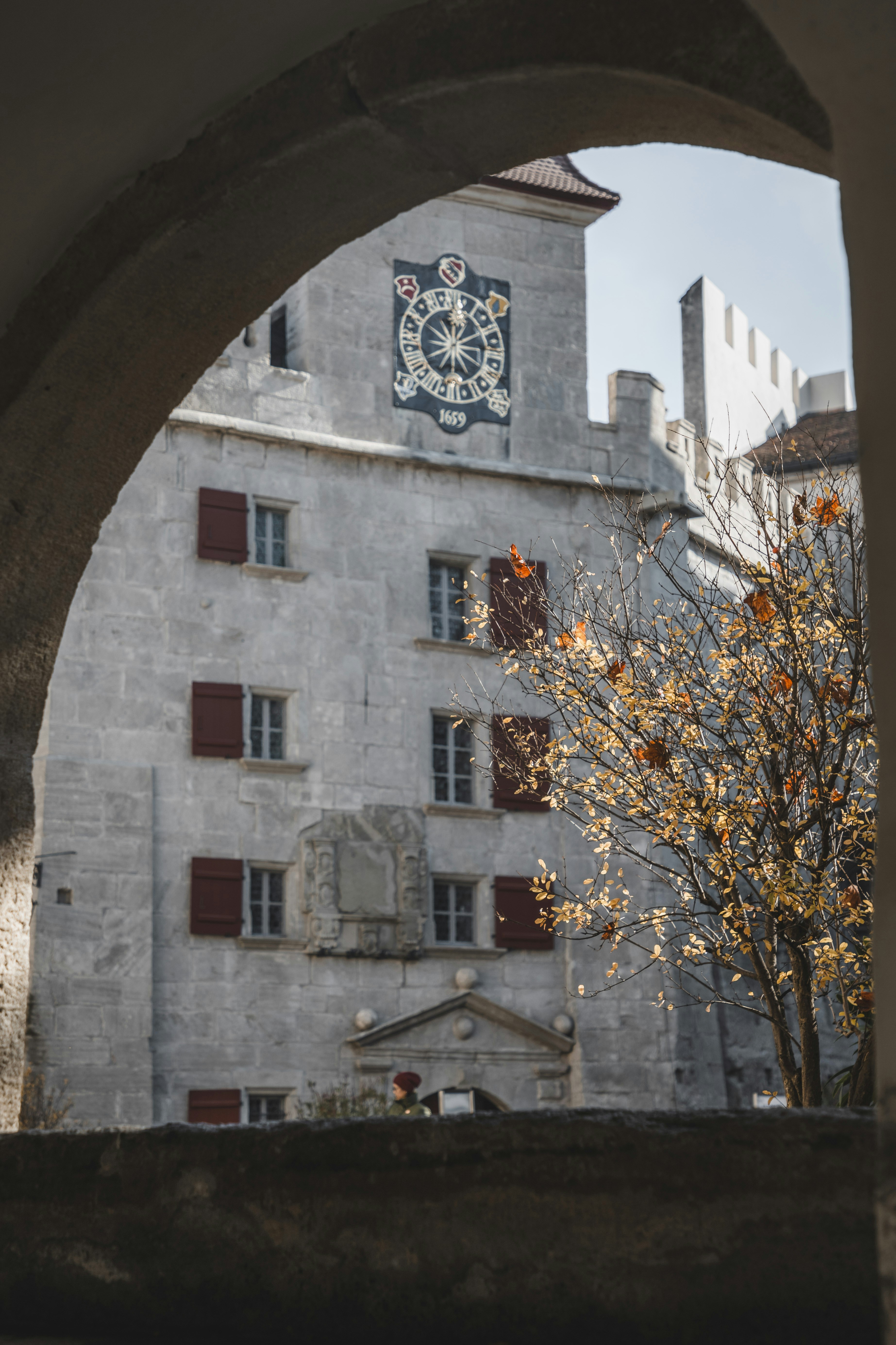Archway View: Clock Crest and Autumn Light on a Historic Facade