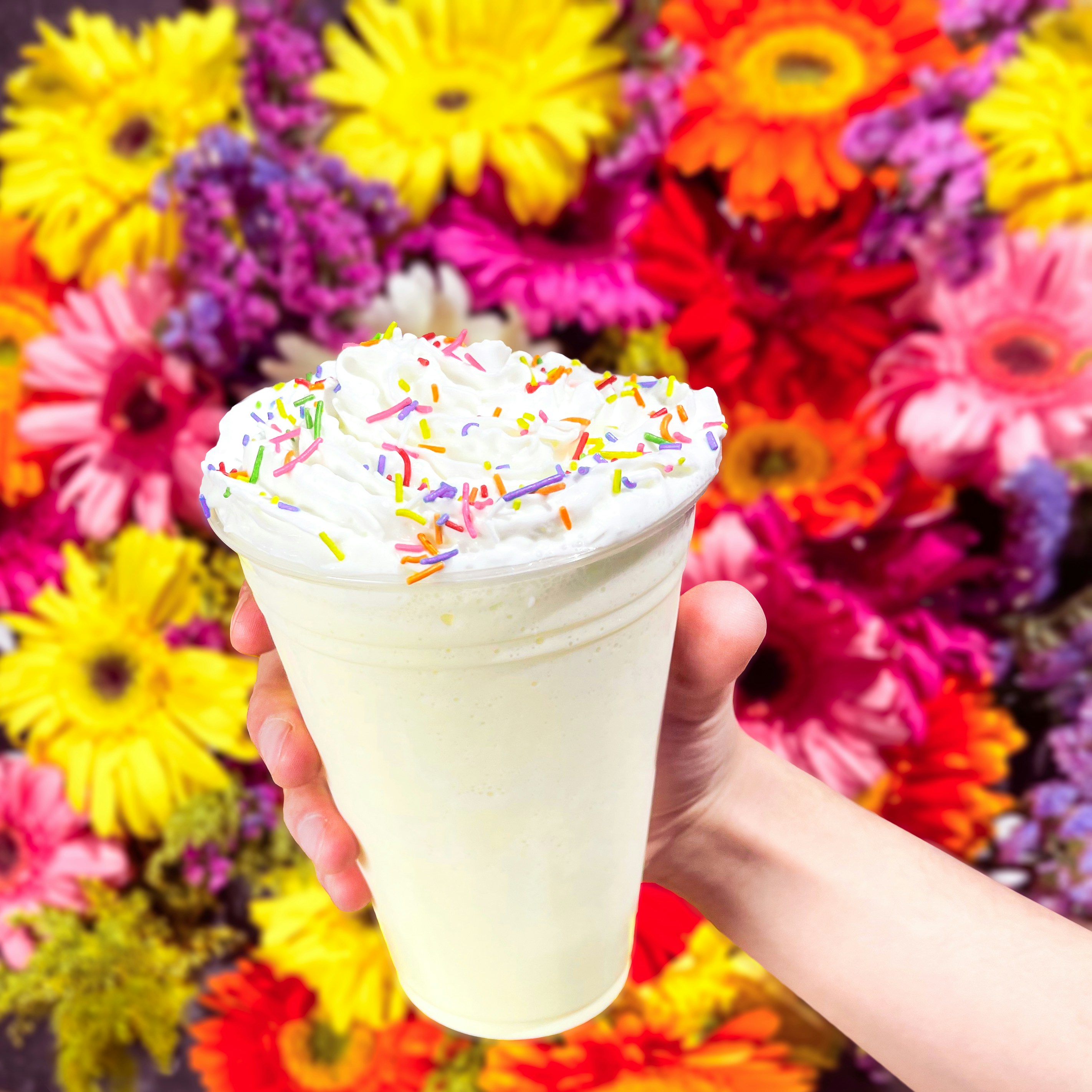 Vanilla Milkshake Crowned with Sprinkles in a Garden of Bold Blooms