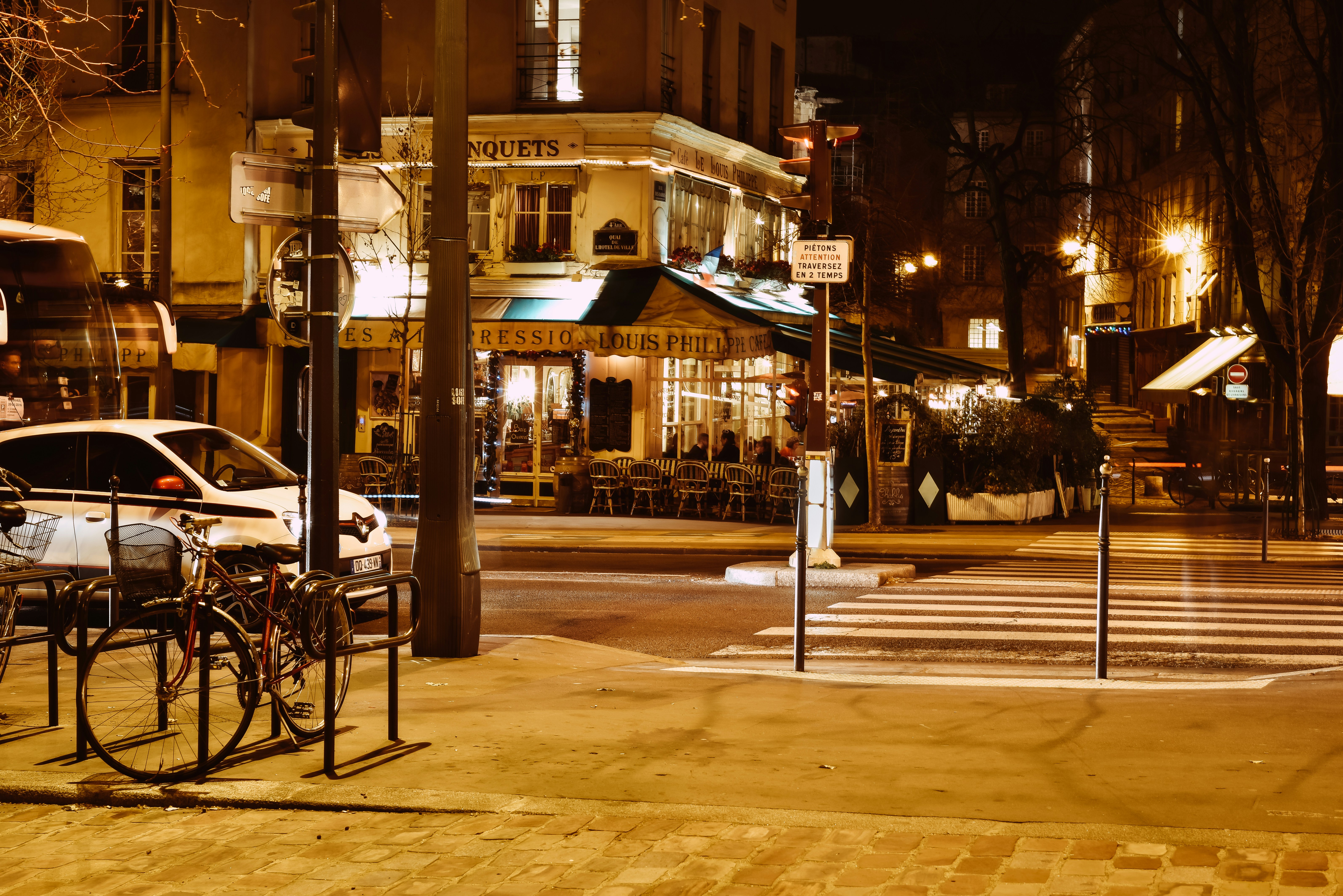 Charming Parisian café illuminated at night, featuring outdoor seating and a cozy ambiance. The scene captures the essence of urban nightlife.