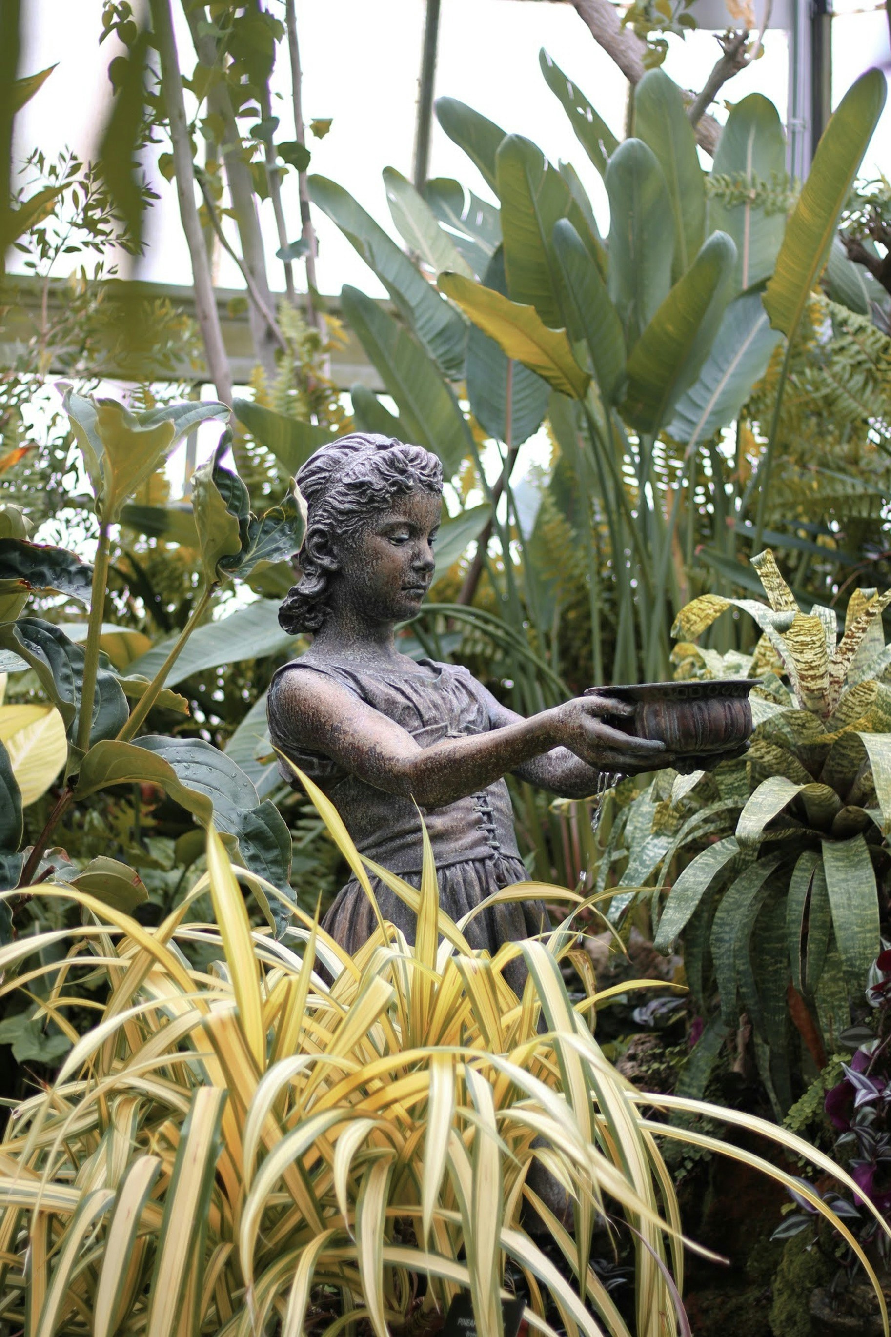 Stone Maiden in a Lush Garden Offering a Bowl