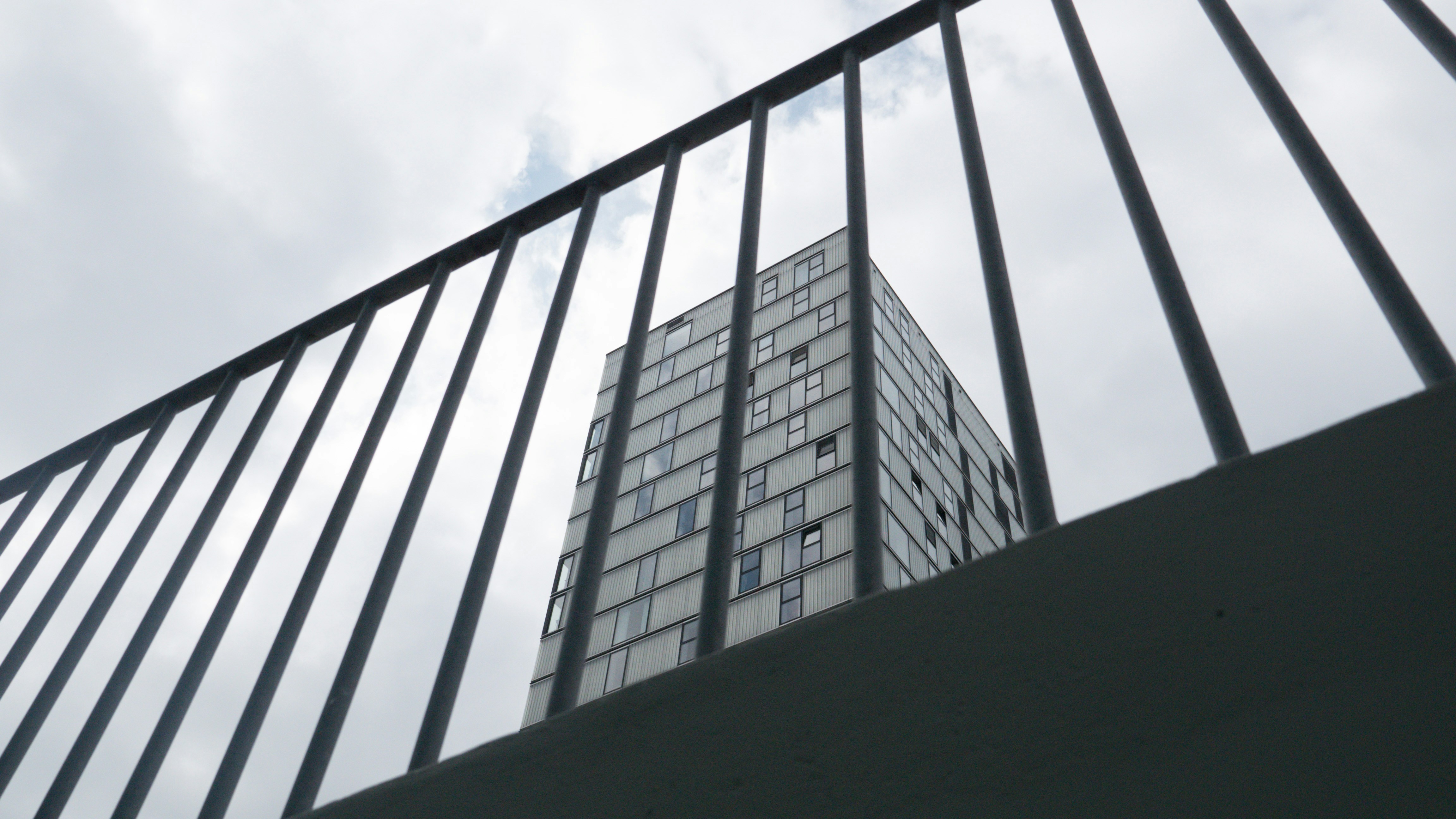 High-rise building framed by vertical metal bars under a cloudy sky.