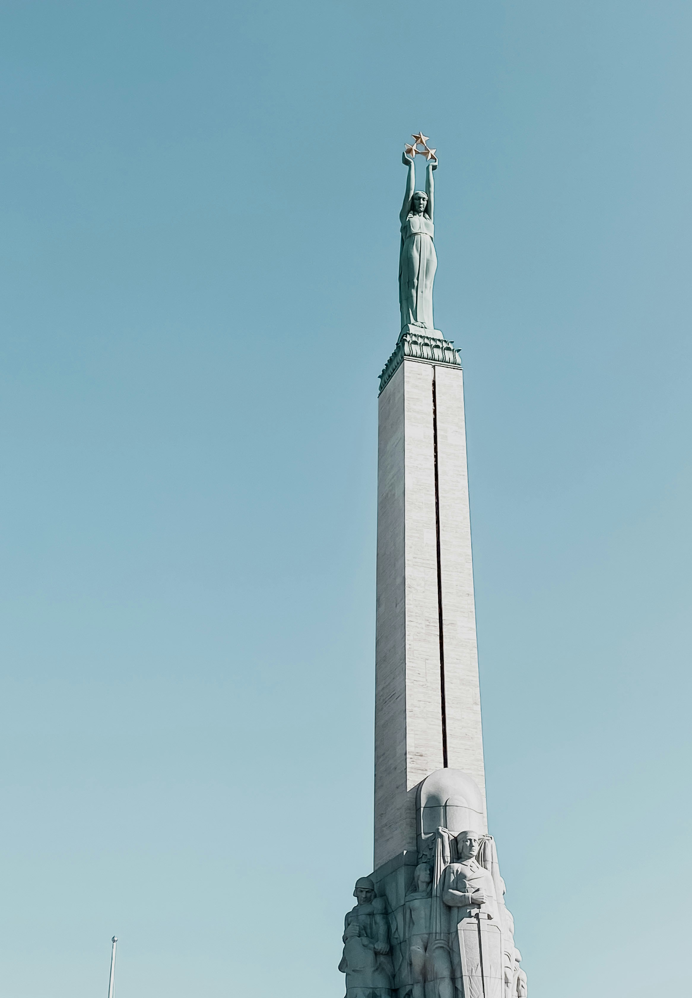Monument featuring a towering statue holding a torch, set against a clear blue sky.