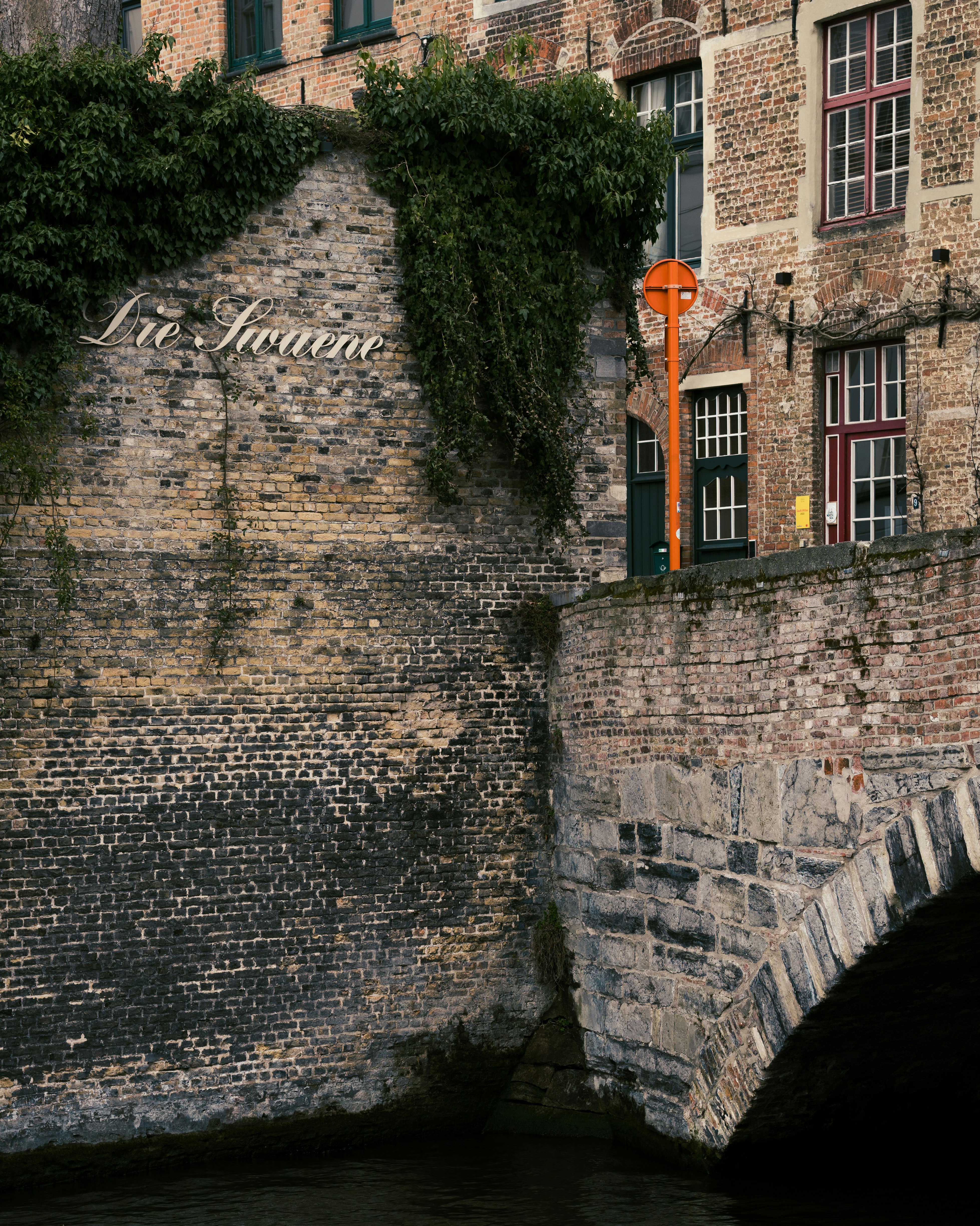 a stone wall with a stone walkway and a brick building with a window