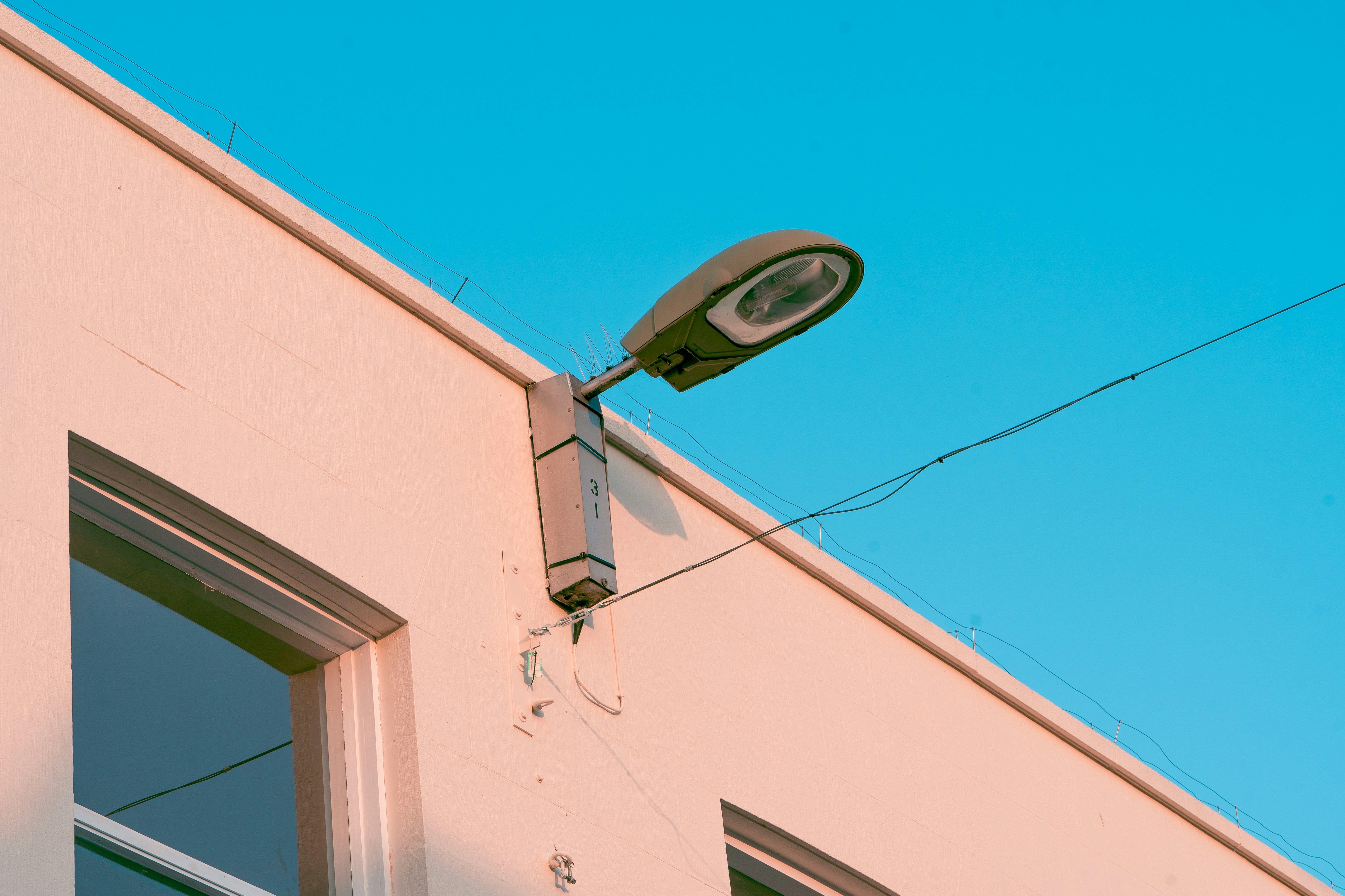Cerulean Sky Over a Minimalist Facade: The Streetlamp’s Quiet Arc