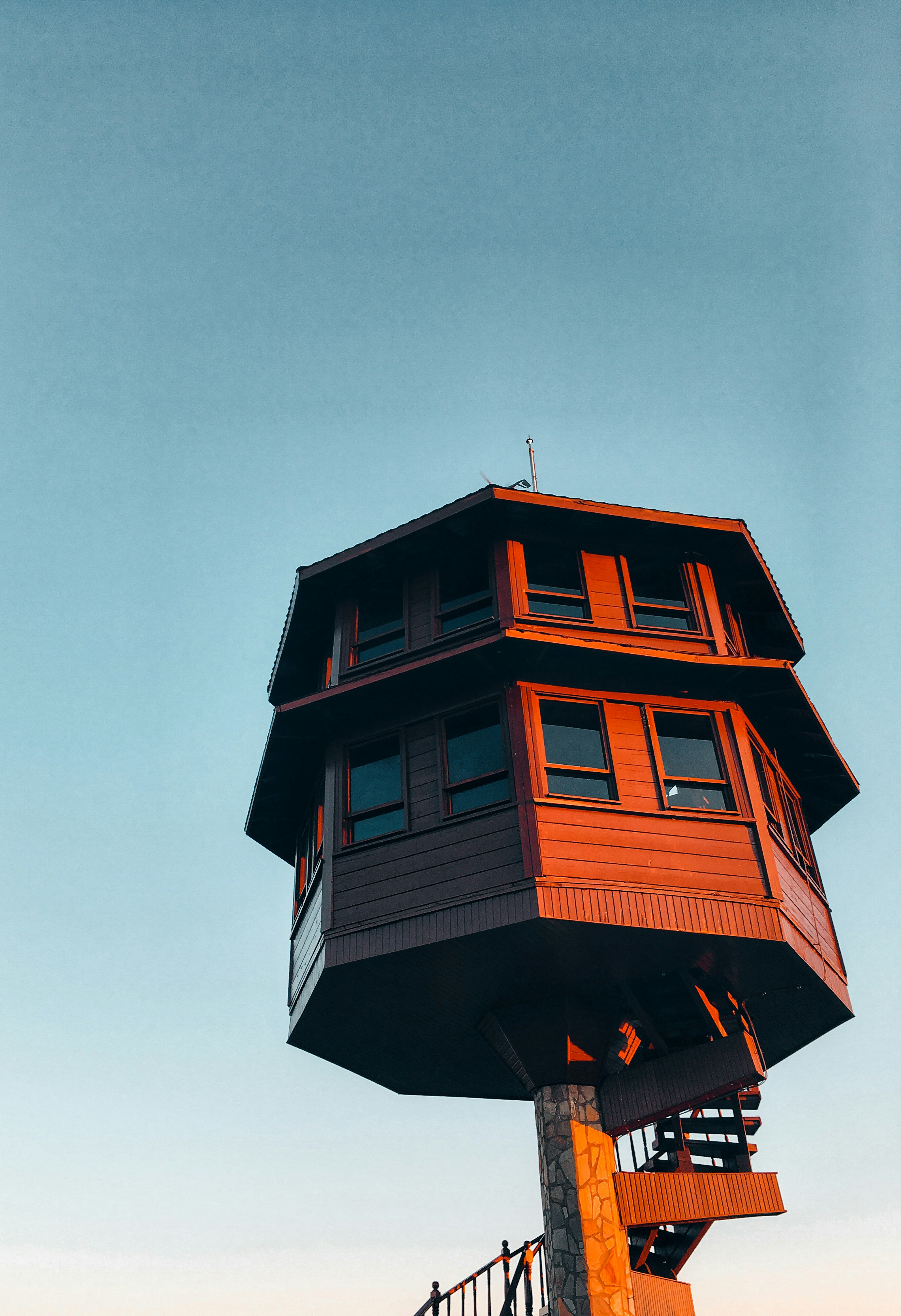 A wooden watchtower stands tall against a clear sky, showcasing its architectural details and inviting exploration.