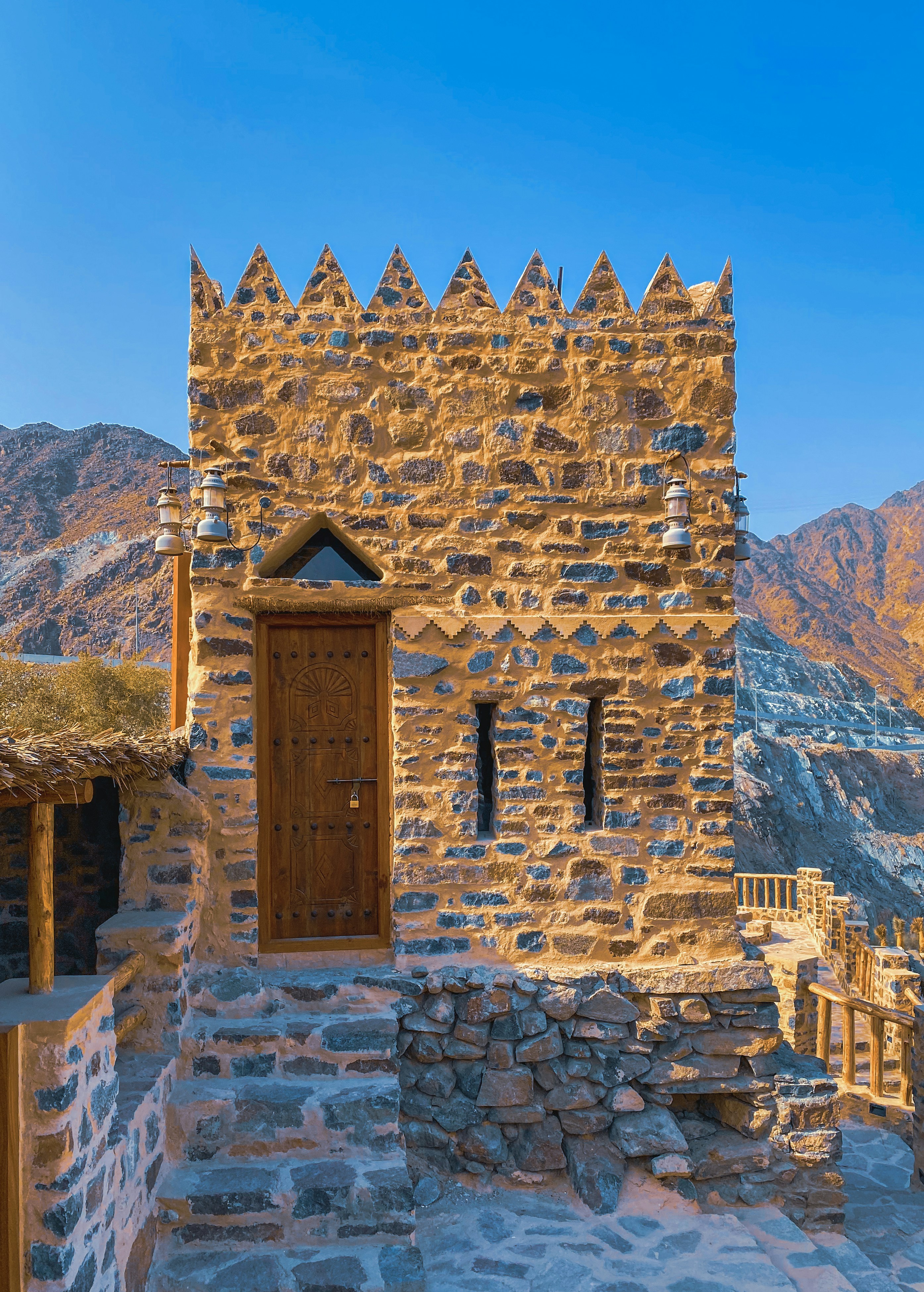Historic stone tower with intricate architecture set against a backdrop of rugged mountains.
