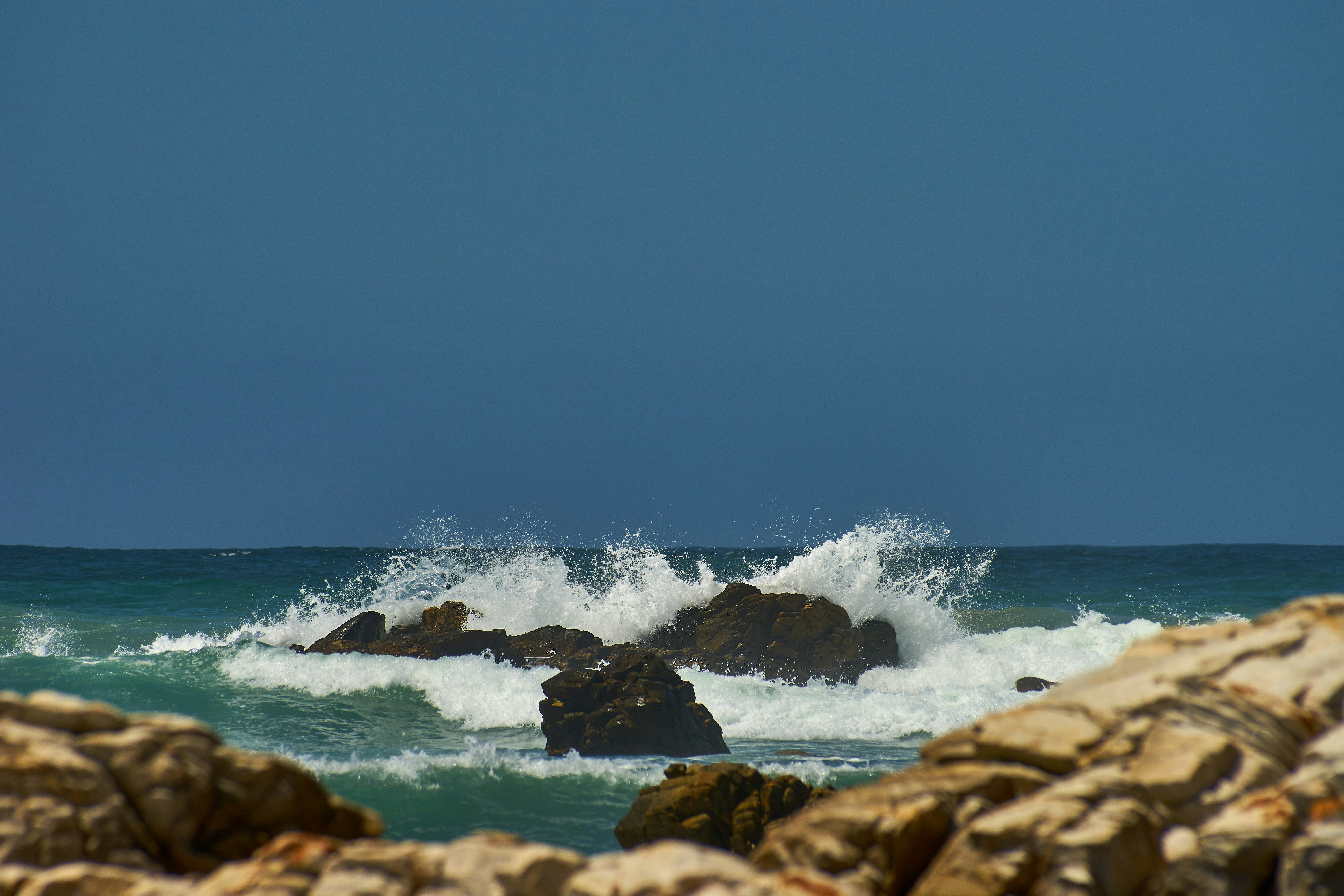 A large body of water surrounded by rocks photo – Free Blue Image on ...