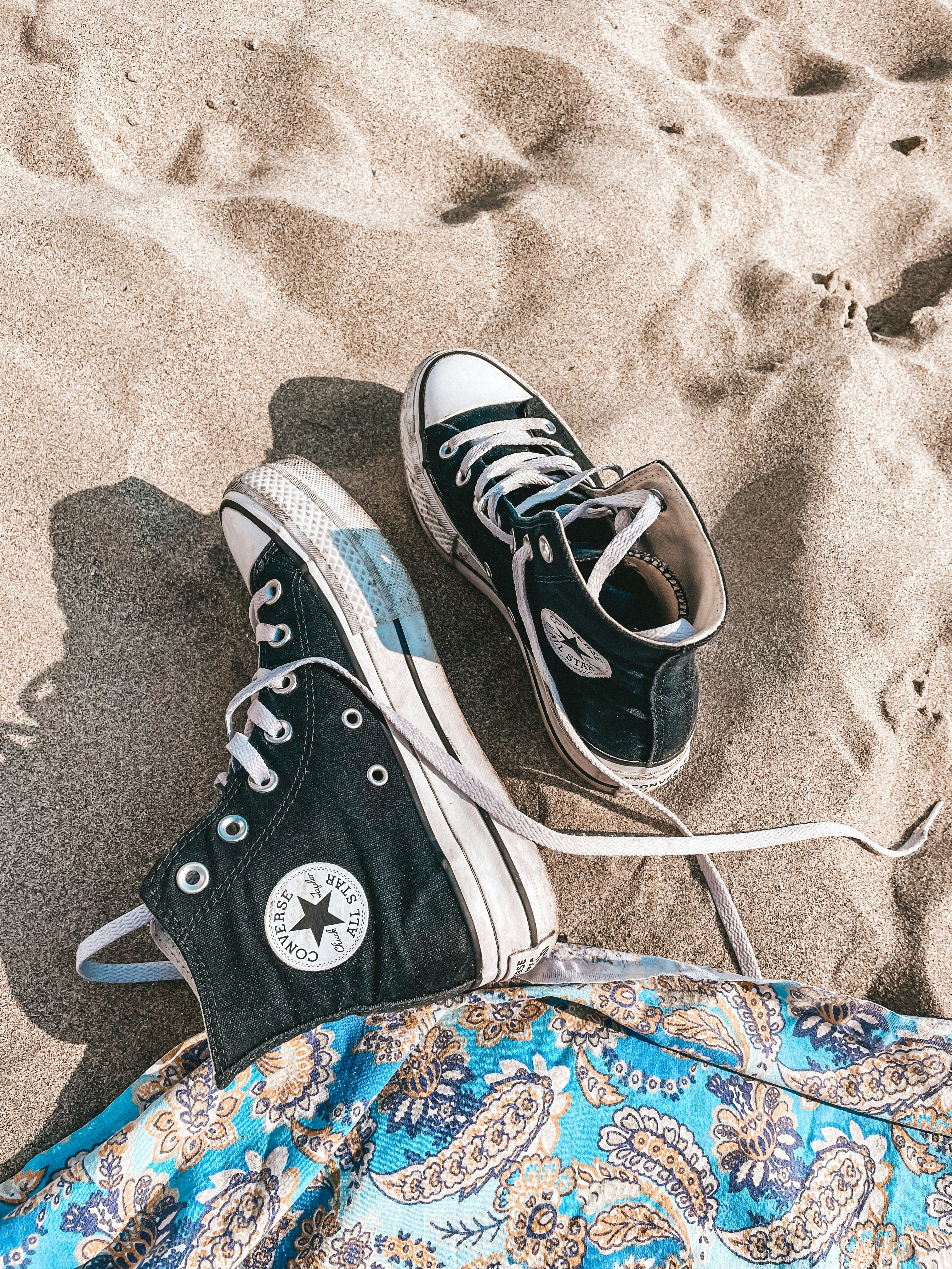 A pair of black and white converse shoes on a blanket photo – Free ...