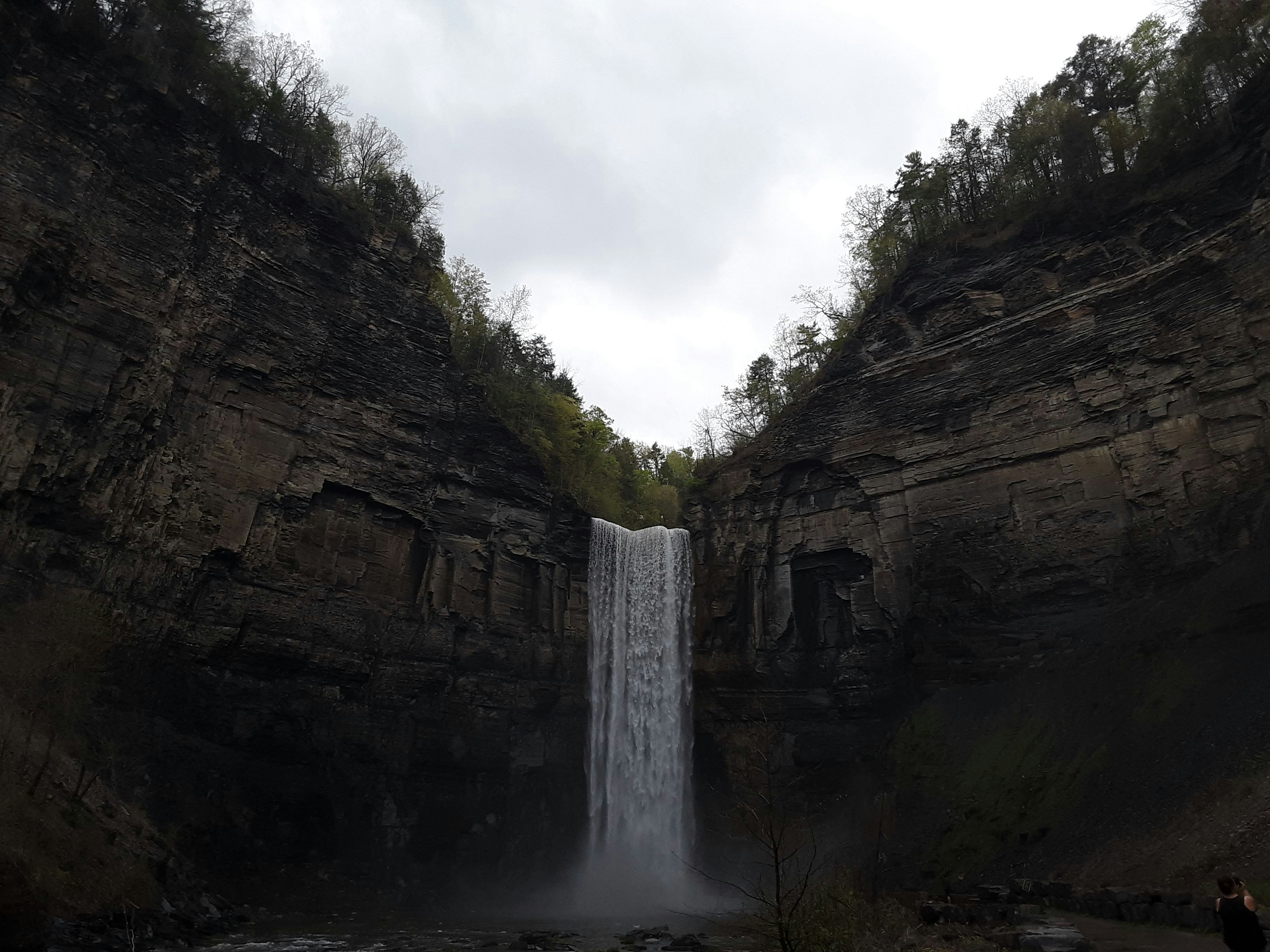 Majestic waterfall cascading down rocky cliffs, surrounded by lush greenery and dramatic rock formations.