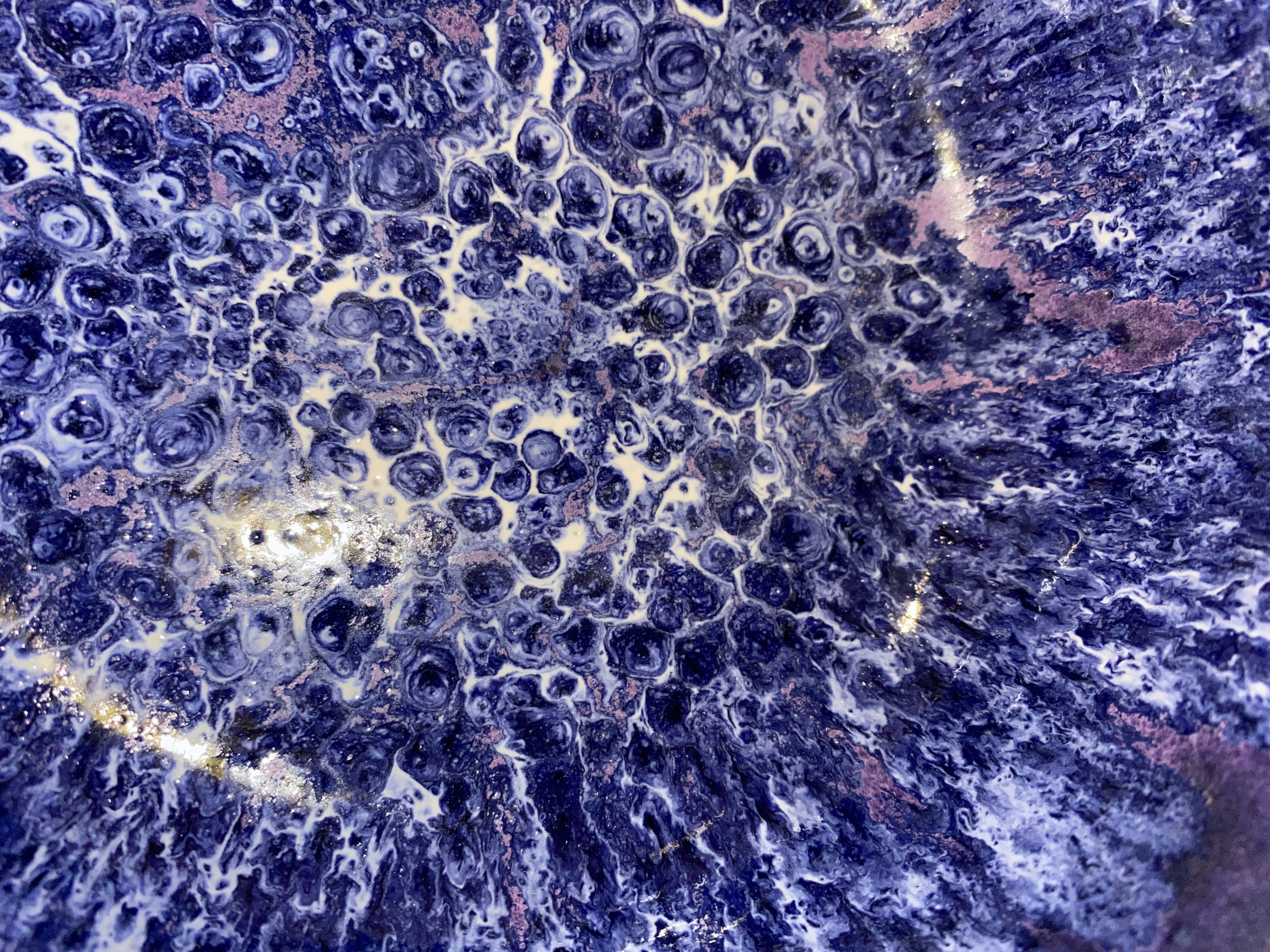 This is a close up image of ceramic piece. It is purple glaze with white glaze layered on top, fired to cone 6 on a white stoneware.