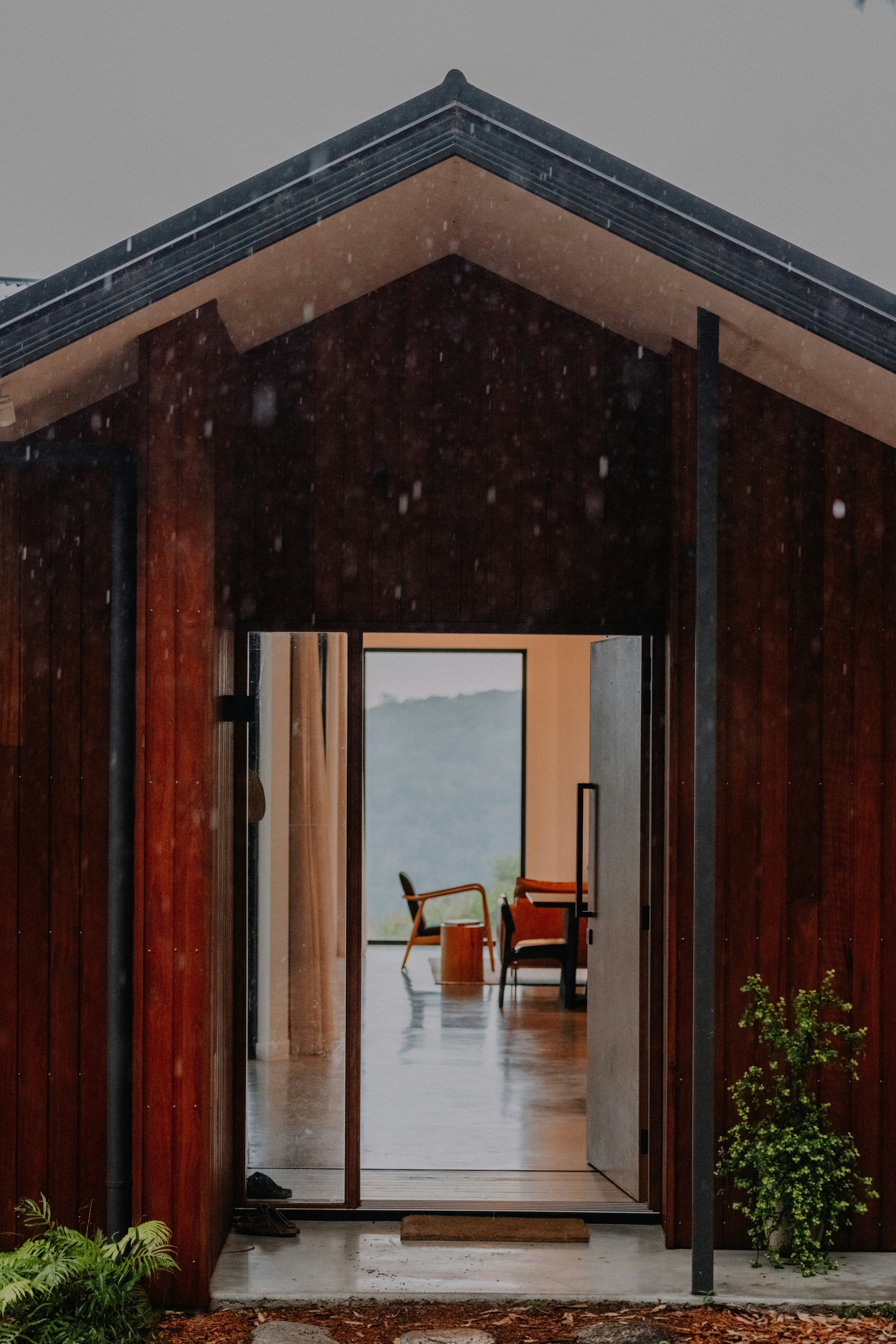 Threshold to Winter Calm: A Cabin's Warm Interior Framed by Falling Snow