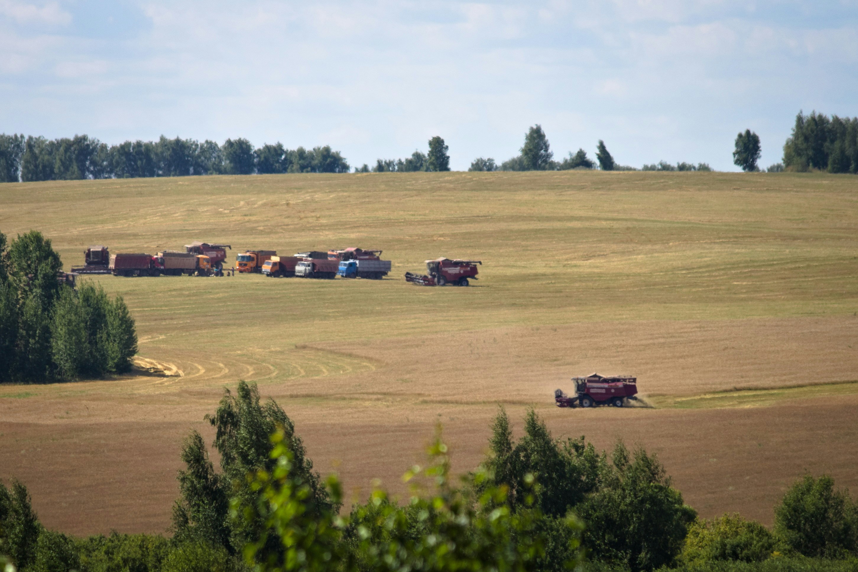 A farm field with a tractor and a trailer in the middle of it photo ...