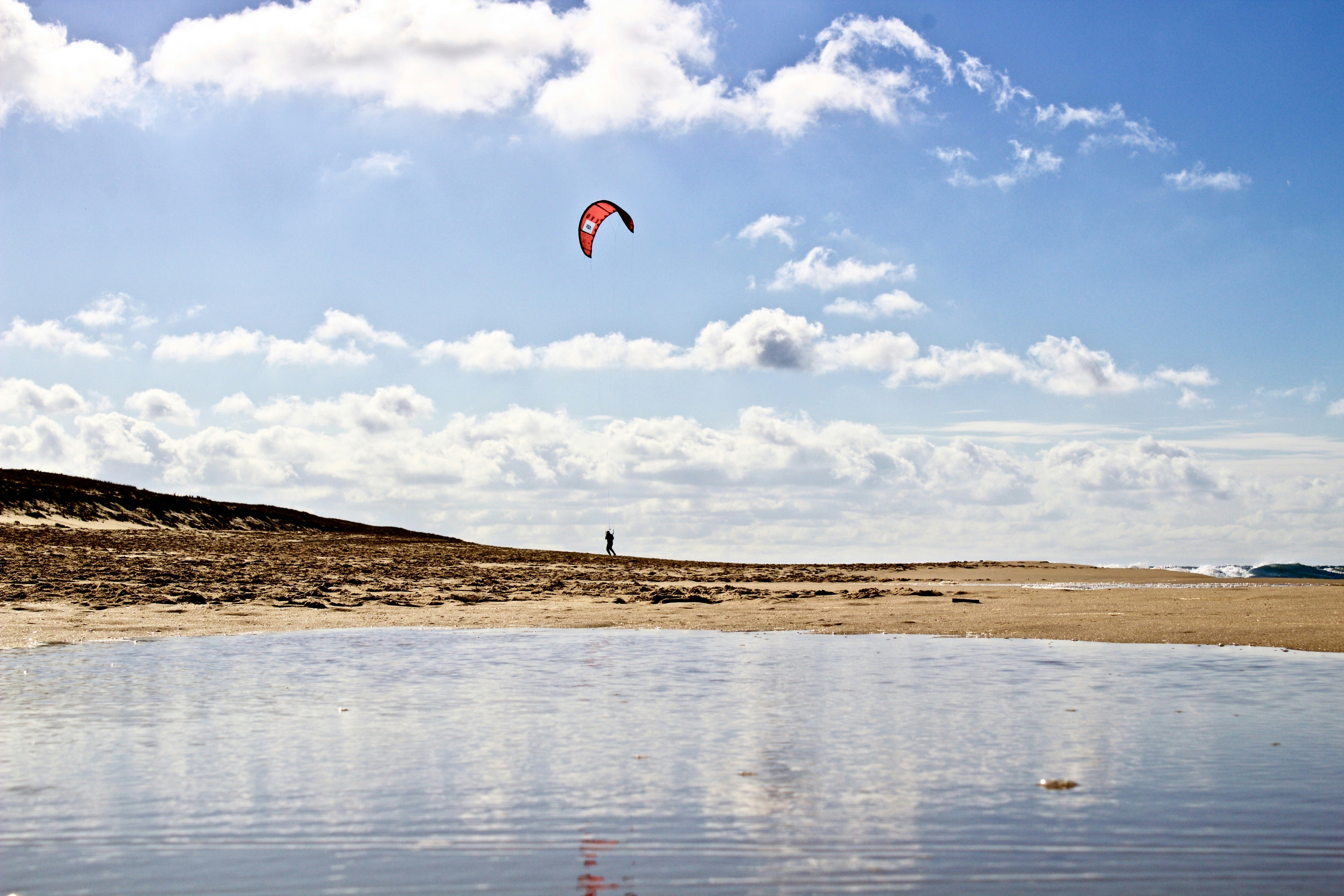 Foto zum Thema Eine Person lässt einen Drachen am Strand steigen ...