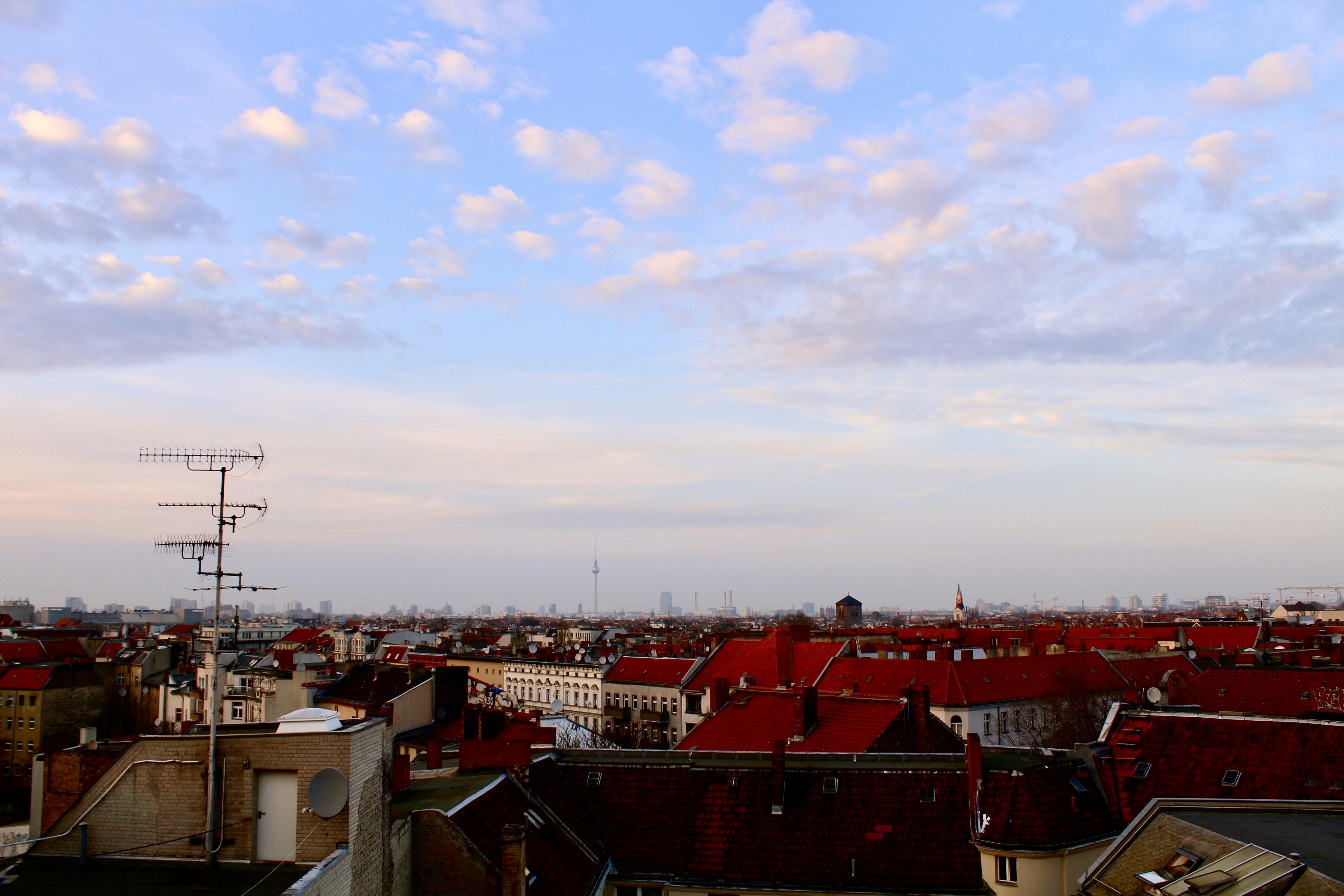 Vast cityscape with red rooftops and scattered clouds under a soft evening sky.