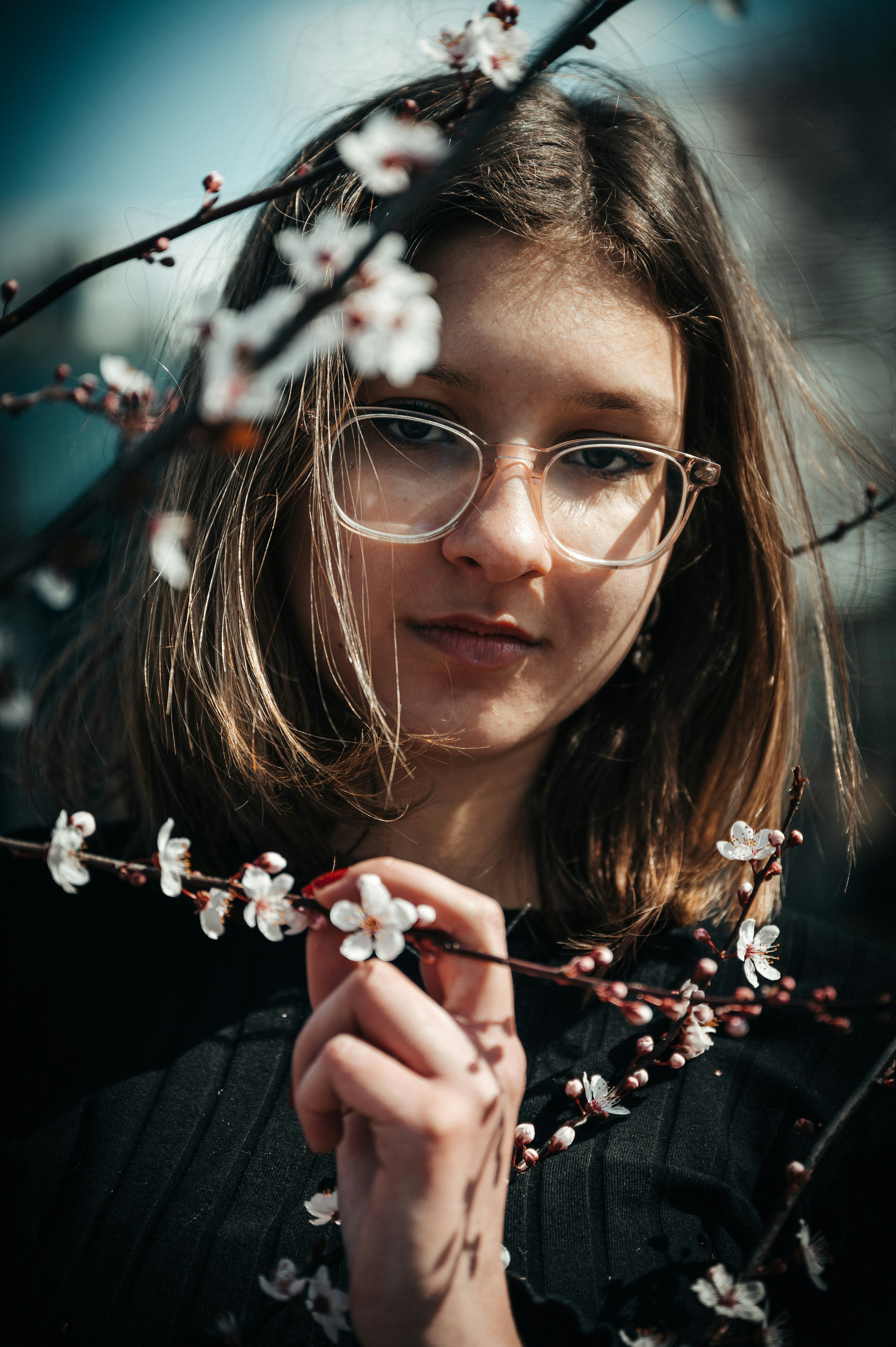 Une femme portant des lunettes et tenant une branche de fleurs de ...