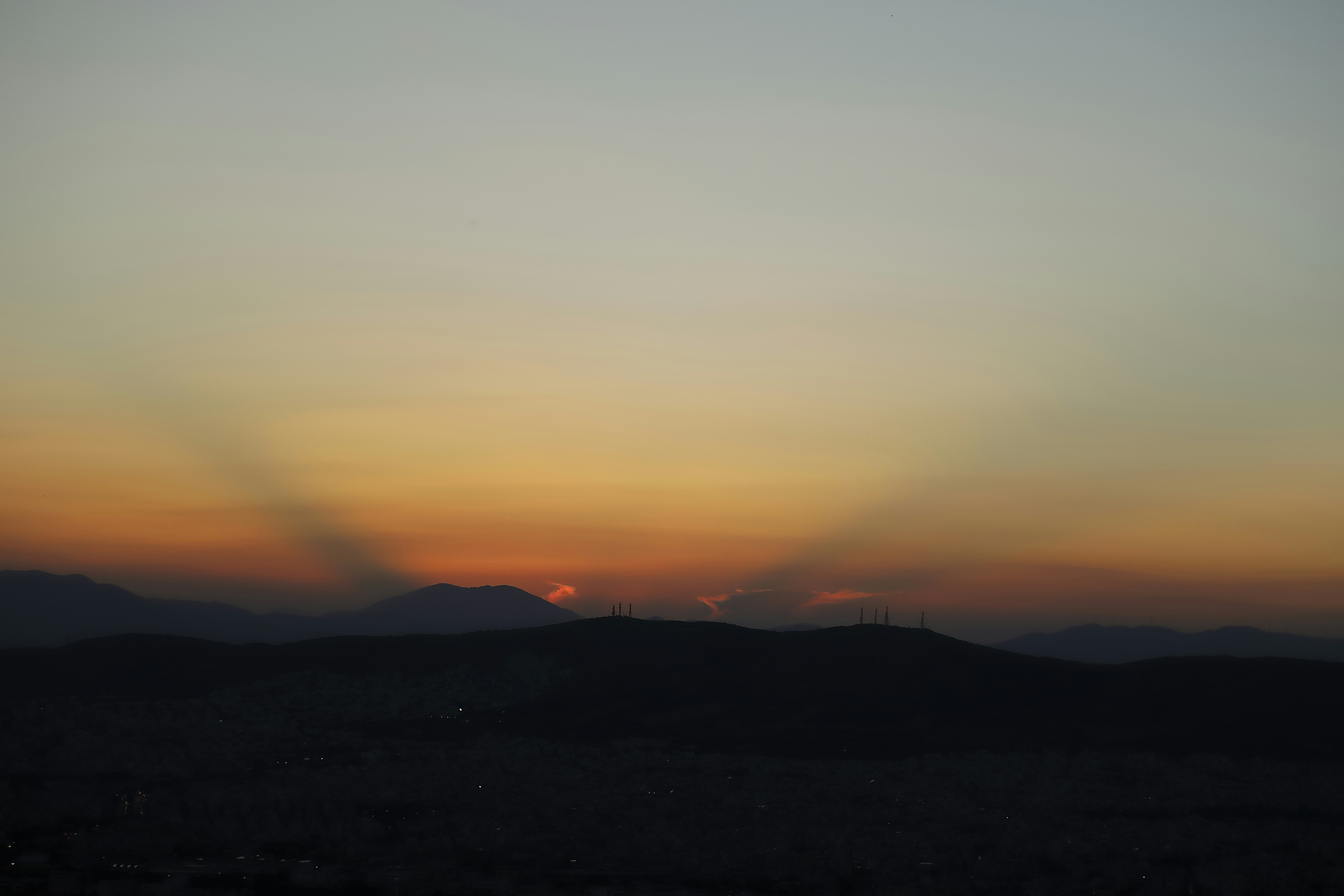 Silhouetted mountains under a gradient sky at sunset, showcasing the interplay of light and shadow.