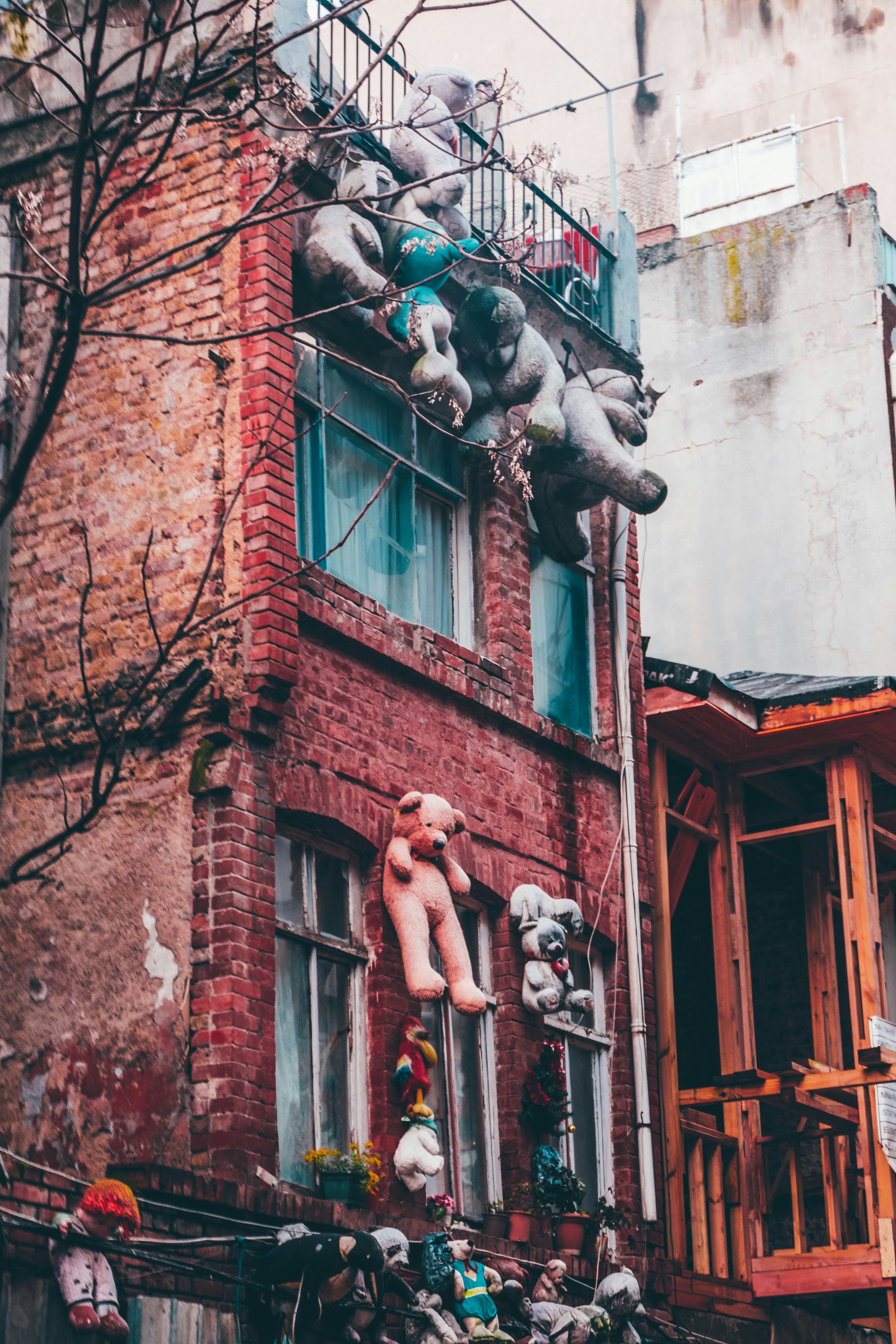 A building with a bunch of stuffed animals hanging from it's windows ...