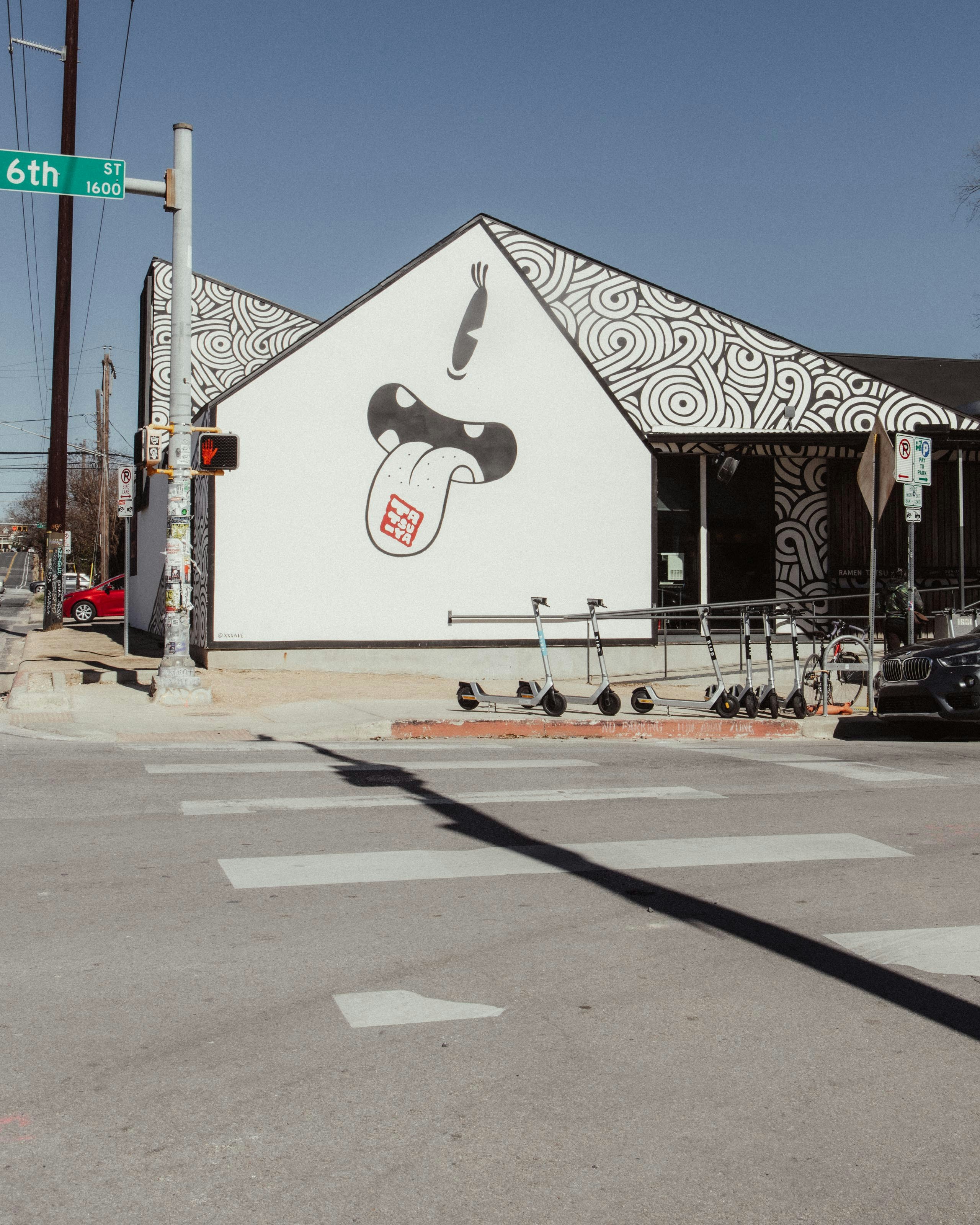 Whimsical mural faces the street, with scooters and crosswalk in the foreground