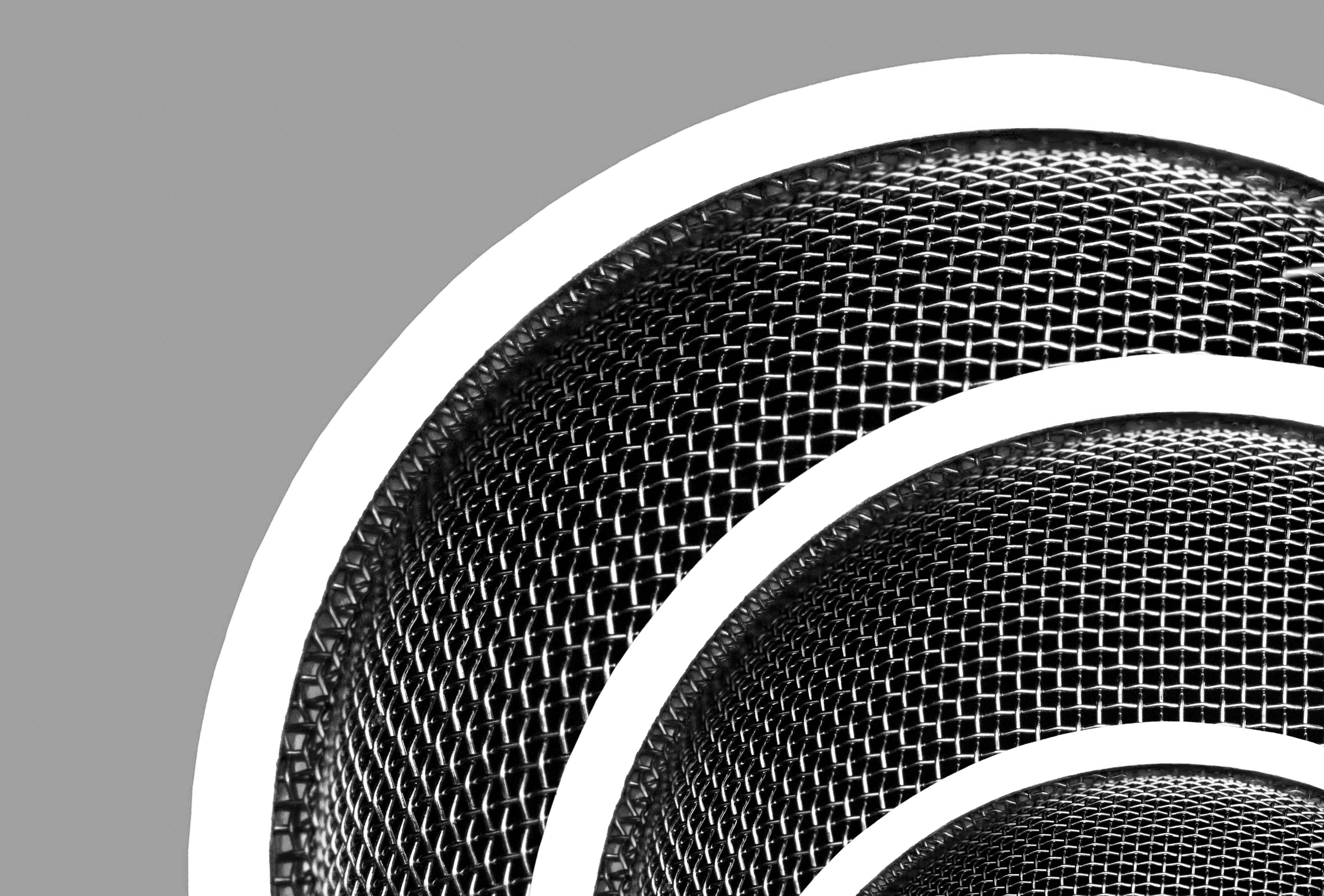 Close-up of a microphone grille showcasing a detailed mesh pattern against a gray backdrop.