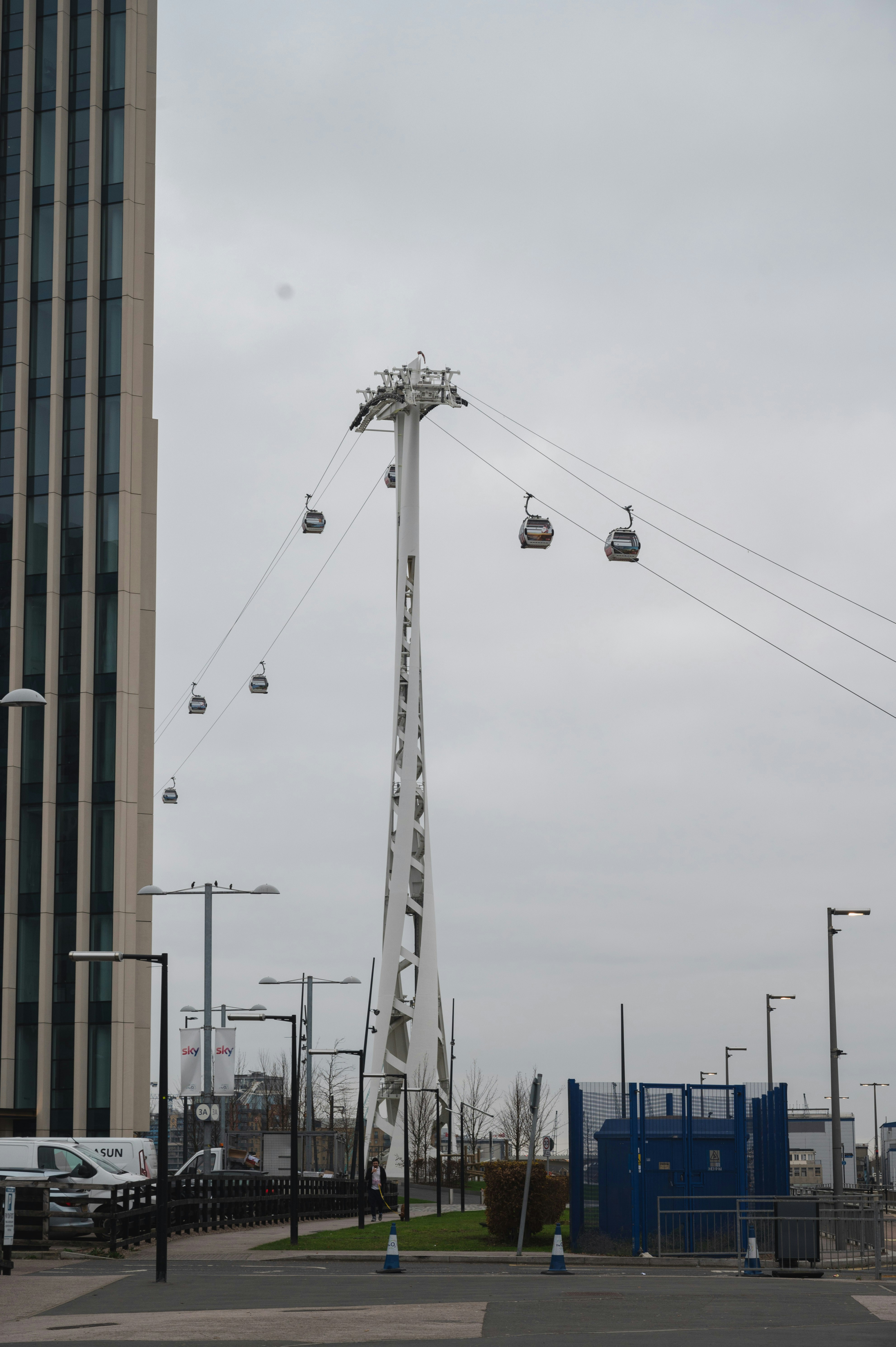 A sleek cable car system ascends from a modern urban landscape under a cloudy sky, showcasing innovative engineering and design.
