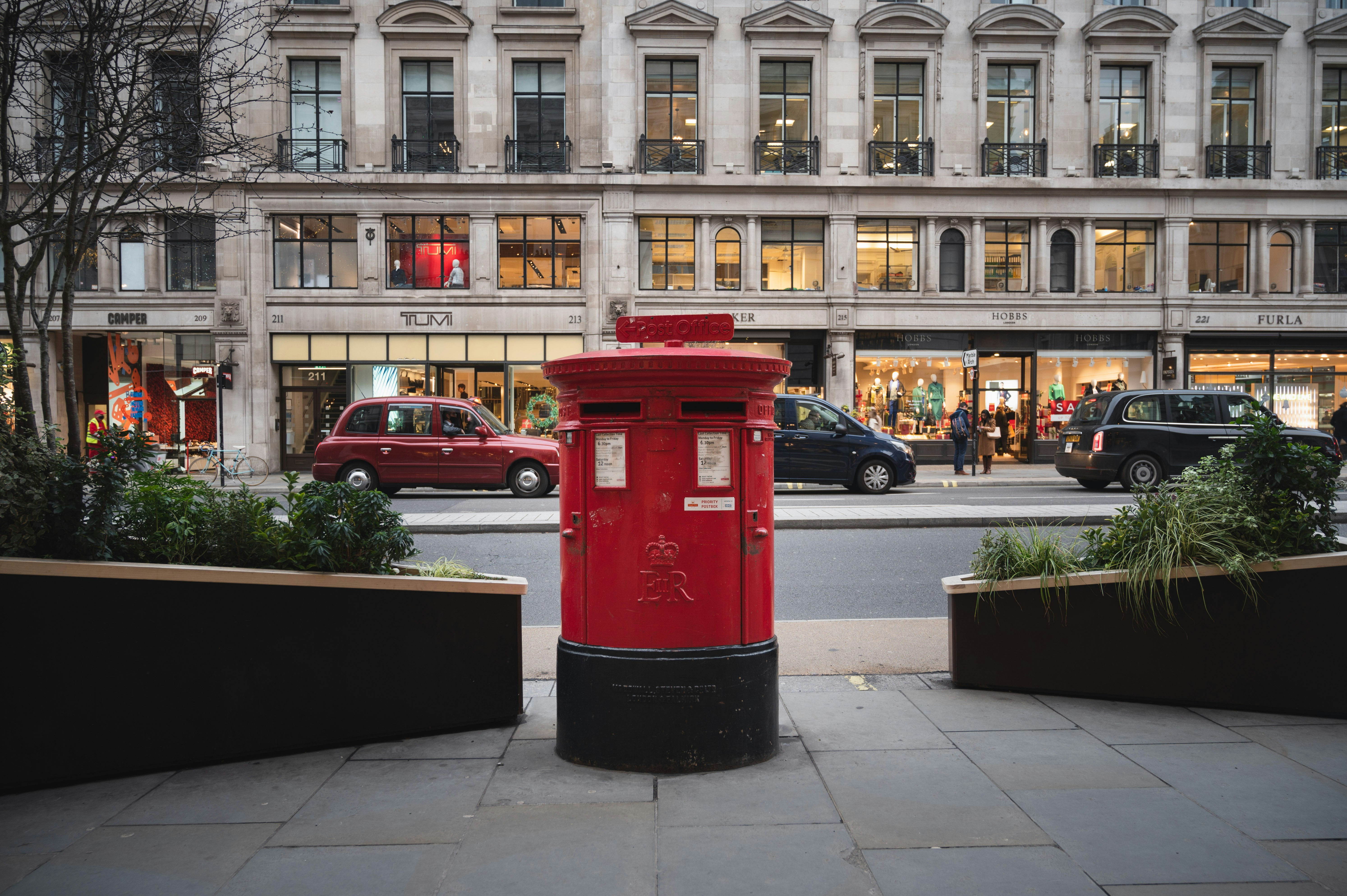 A red post box sitting on the side of a street photo – Free Brown Image ...
