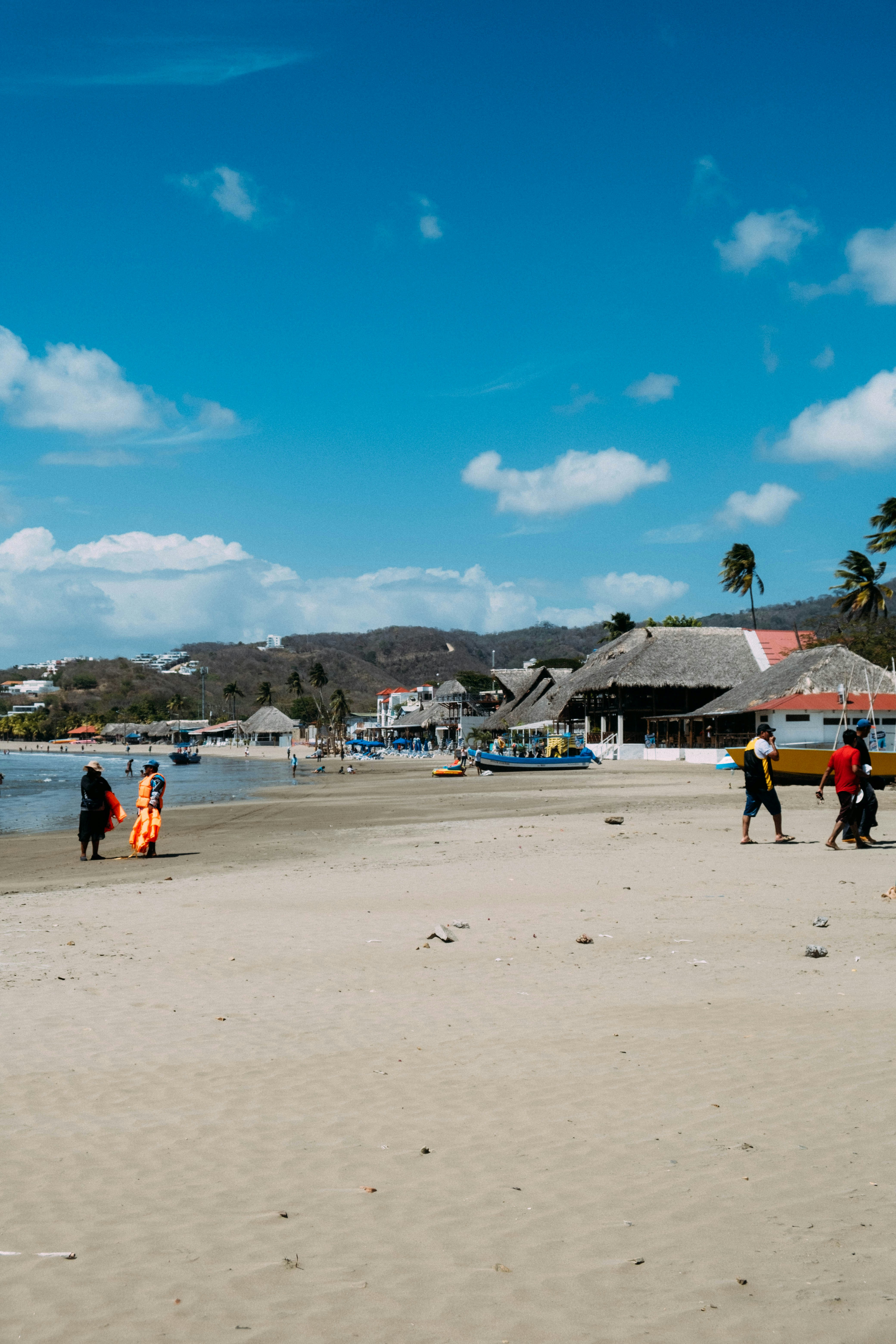 Thatched Cabins by the Tide: A Lively Beachfront Scene