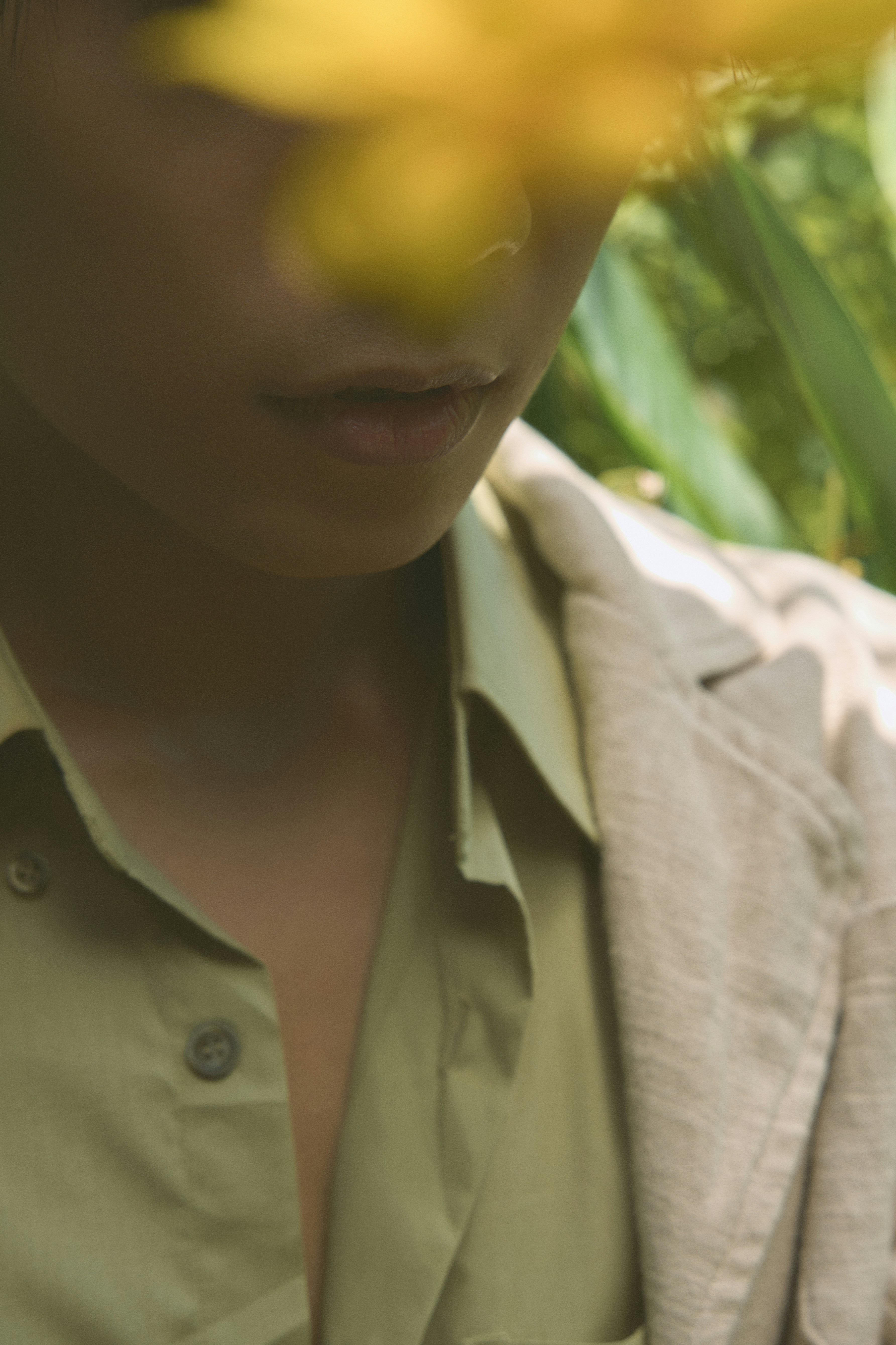A close-up of a person partially obscured by vibrant yellow flowers, blending human presence with the lush greenery around them.