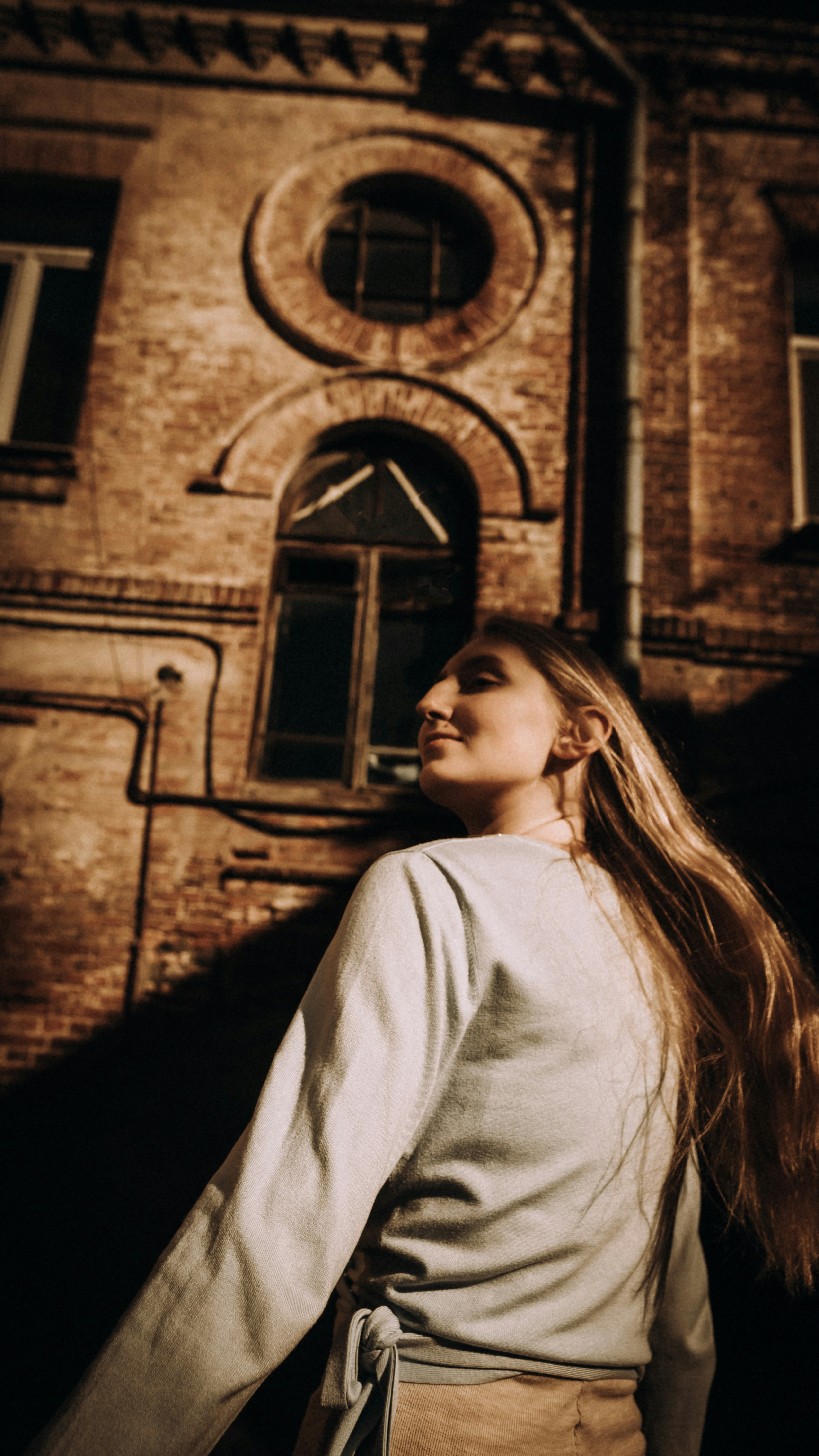 Night Portrait on Brick Facade: The Grinning Arch and the Figure in Soft Light