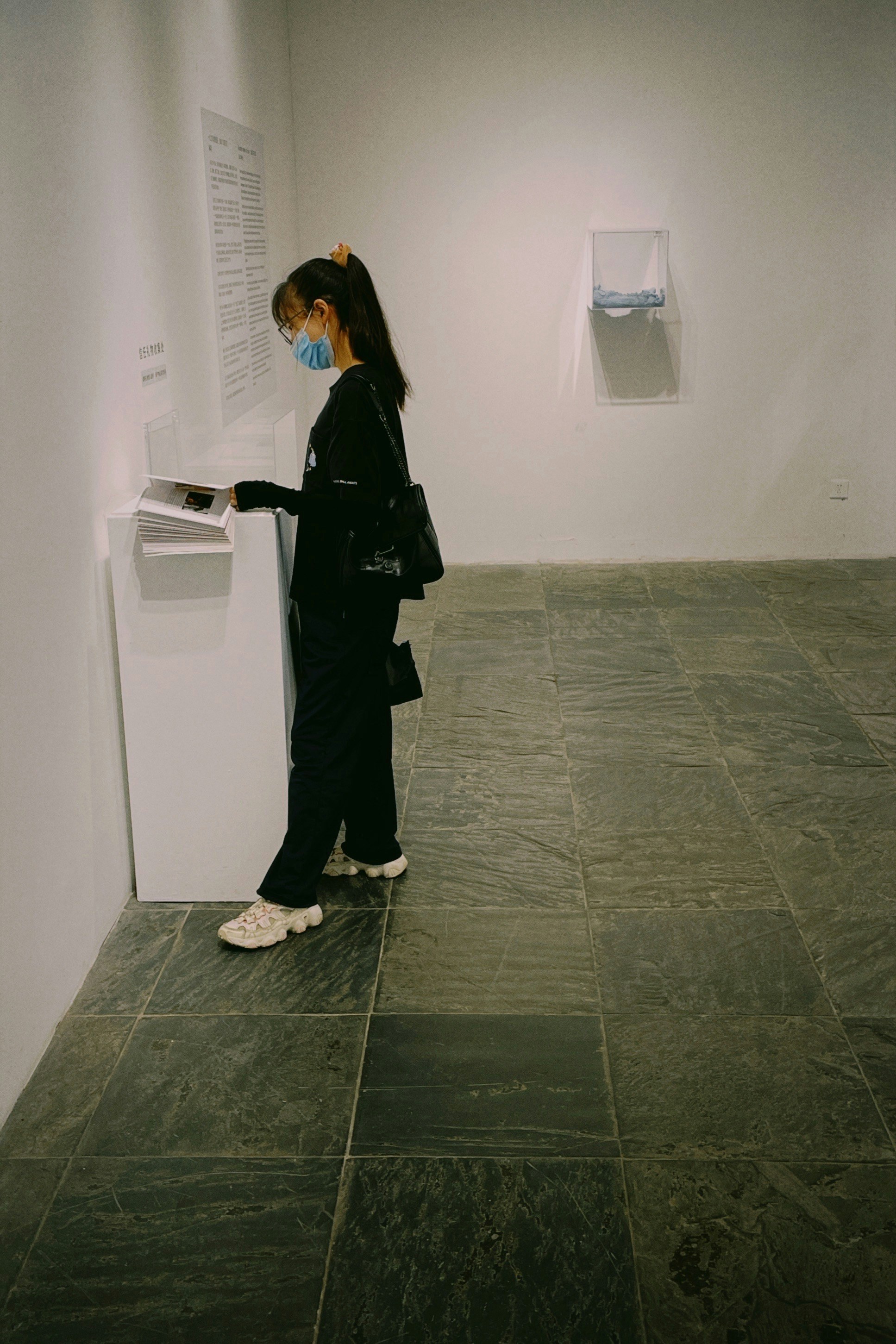 Visitor interacting with an informational display in a minimalist art gallery. A soft ambiance complements the exploration of art.