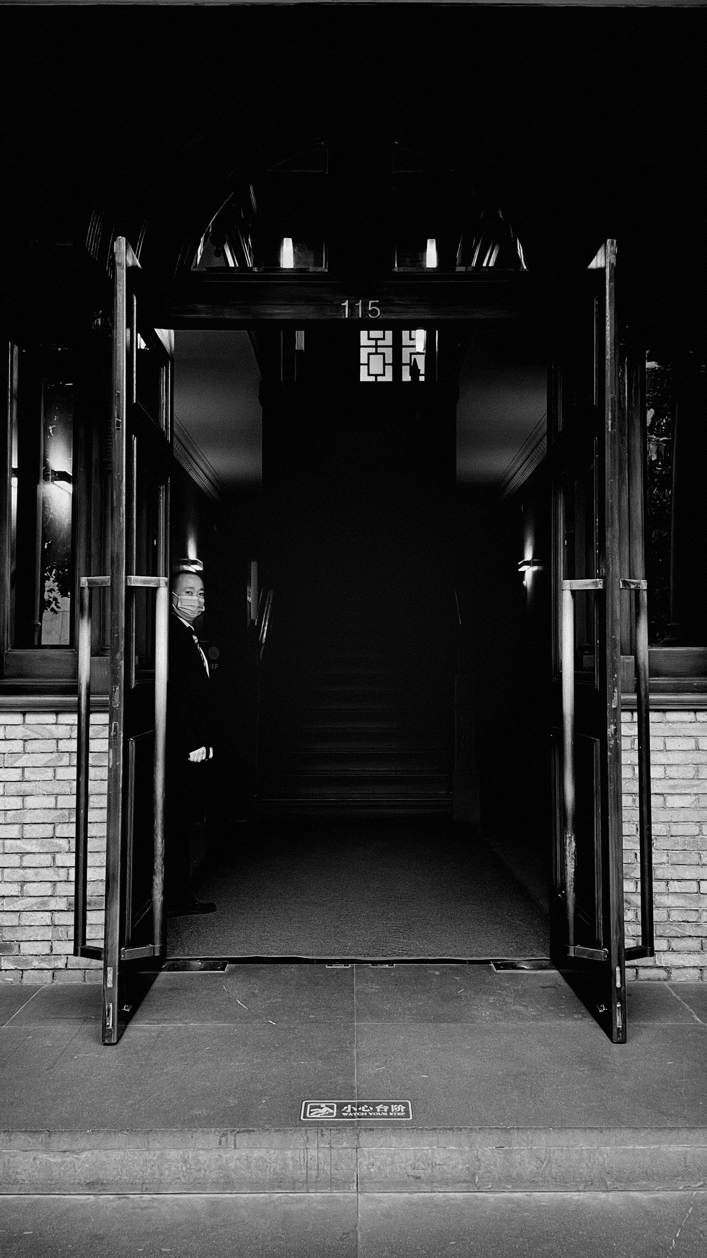 A black and white photo of a man entering a building photo – Free Black ...