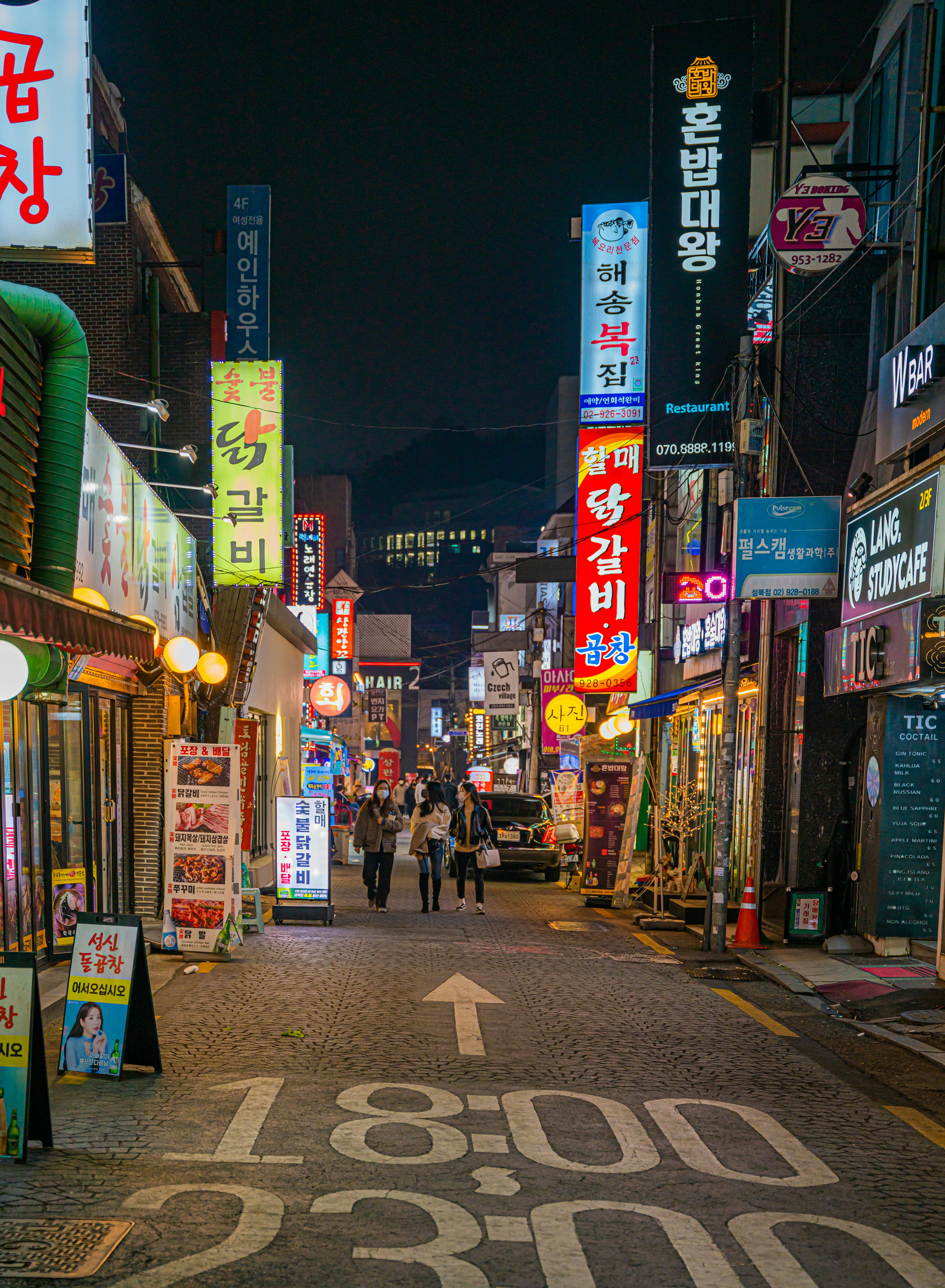 Vibrant street scene filled with illuminated signs and bustling eateries, capturing the essence of nightlife in a busy urban area.