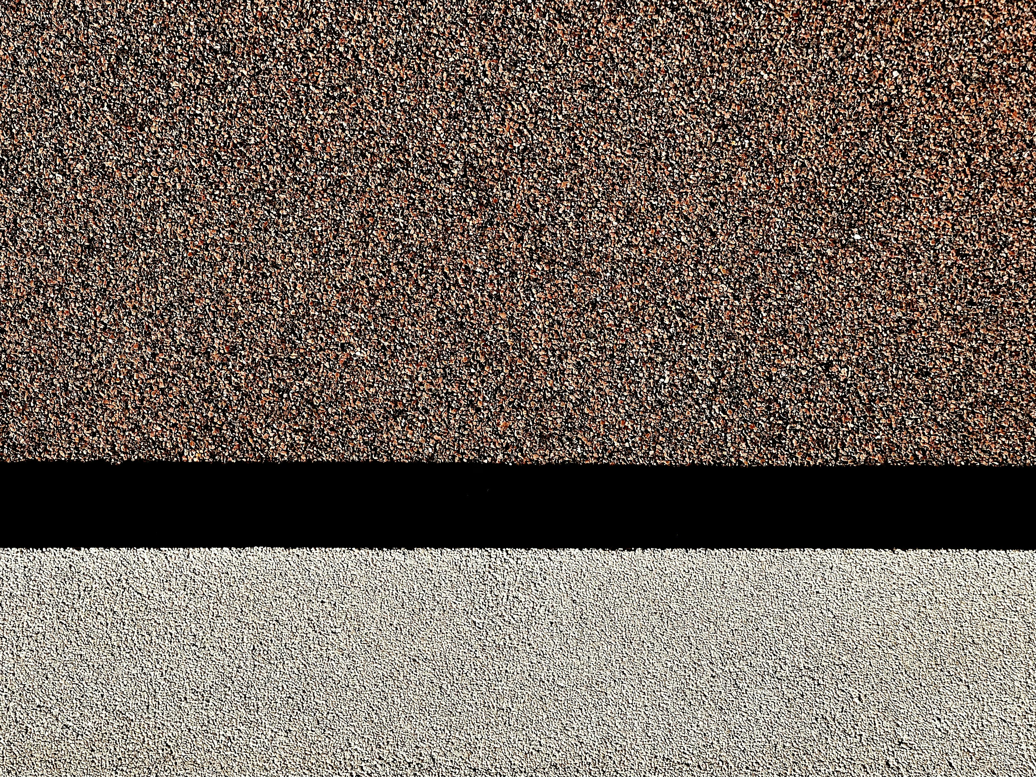 Close-up of contrasting surfaces featuring a rough granite texture above a smooth concrete strip, separated by a dark line.