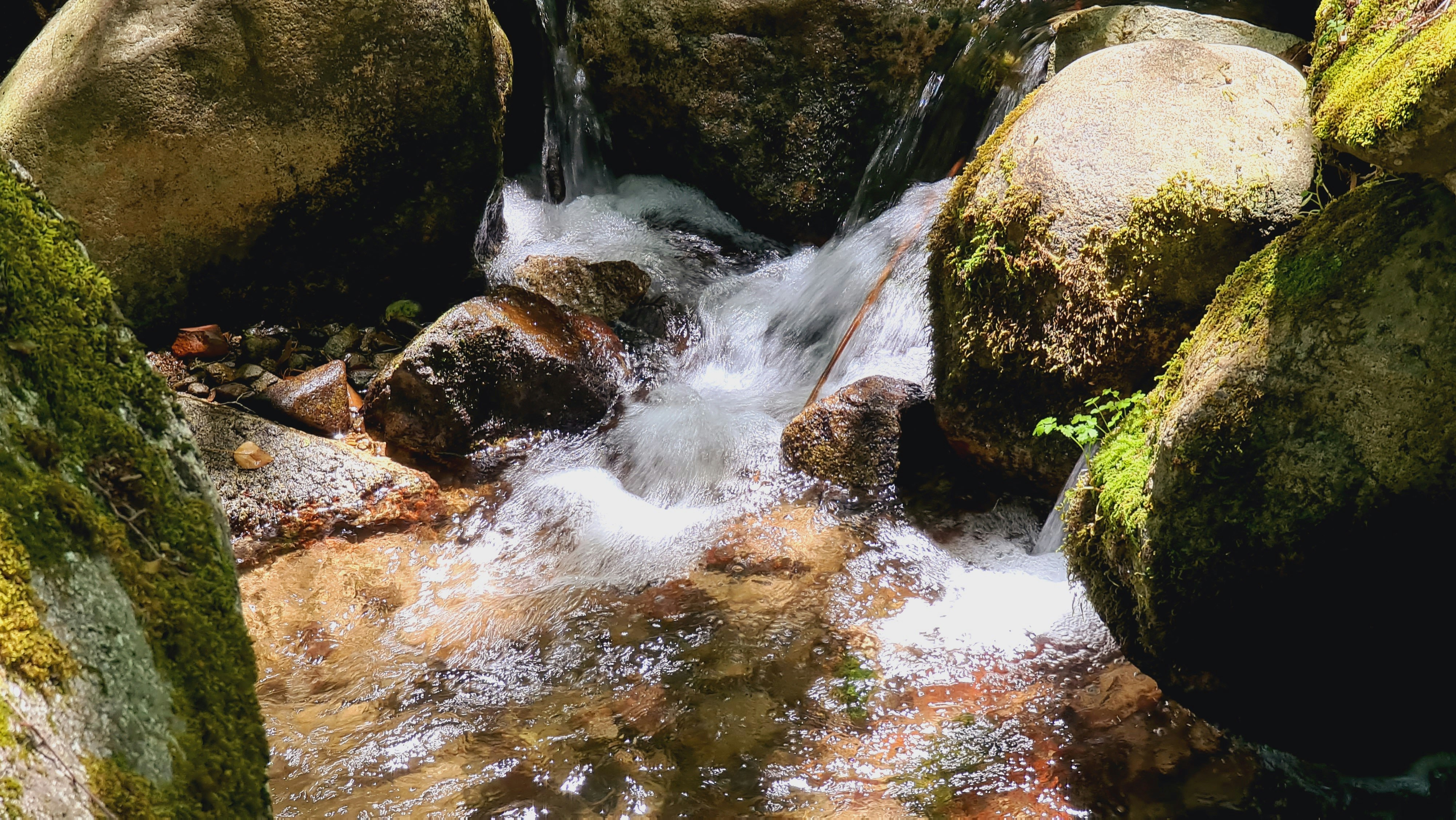 A stream of water running between two large rocks photo – Free Water ...