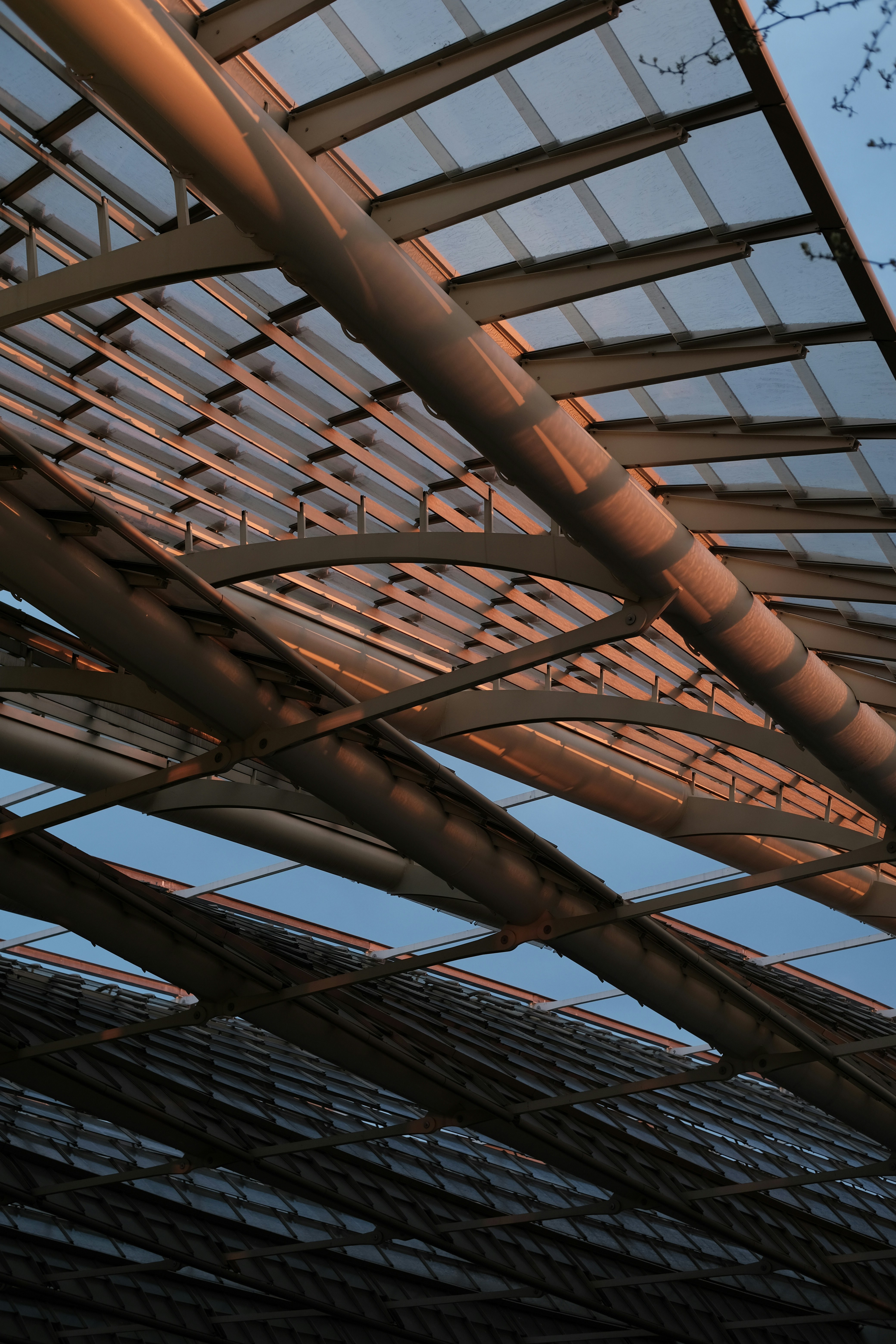 Intricate patterns of a modern architectural canopy illuminated by soft evening light.
